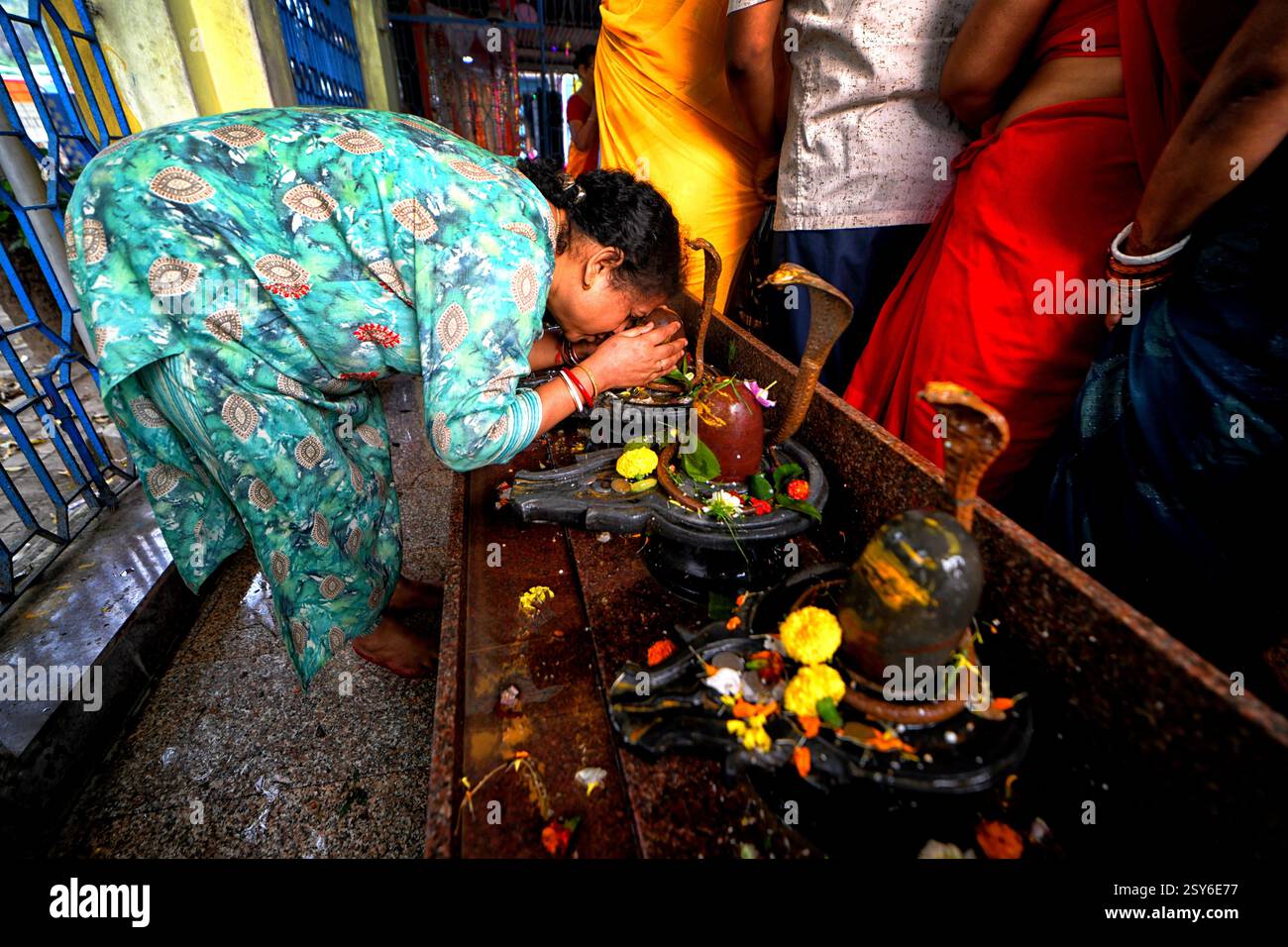 A devotee seen offering prayer over a Shivling (a symbol of Lord Shiva ...