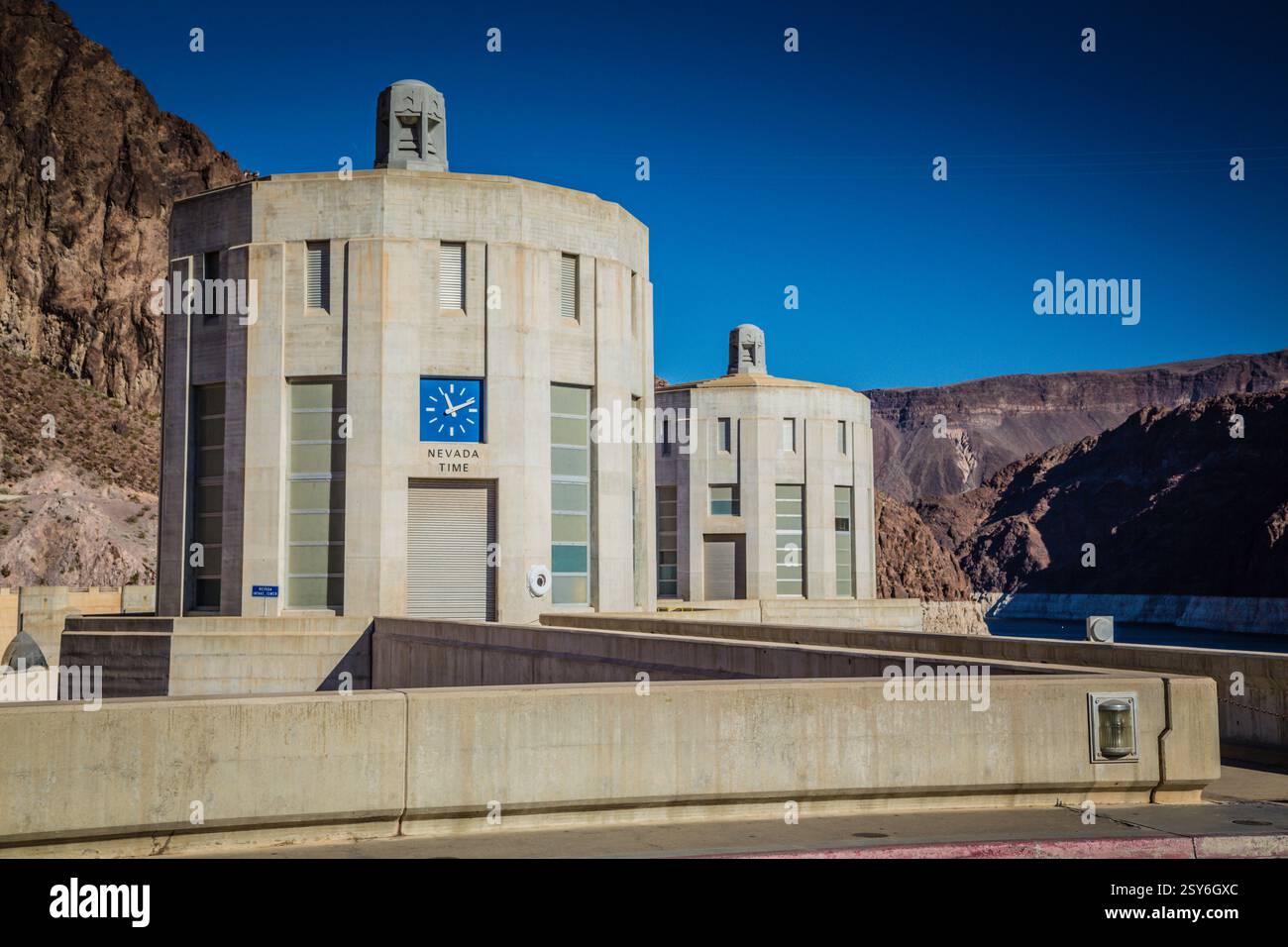 Clock tower with a blue face sits in front of a wall. The clock is on ...