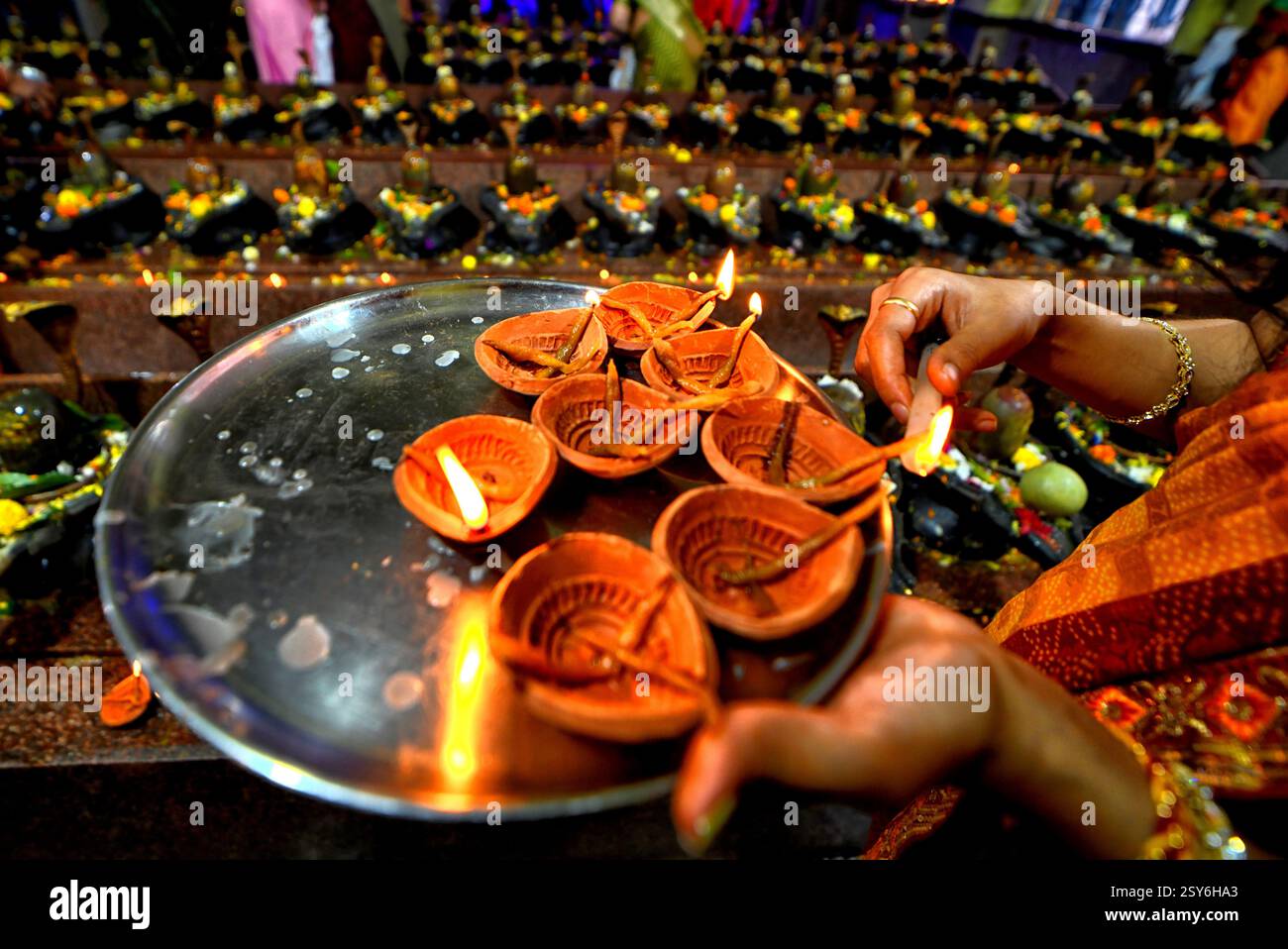 A devotee seen offering Diya /earthen lamp over the Shivling's (symbol ...