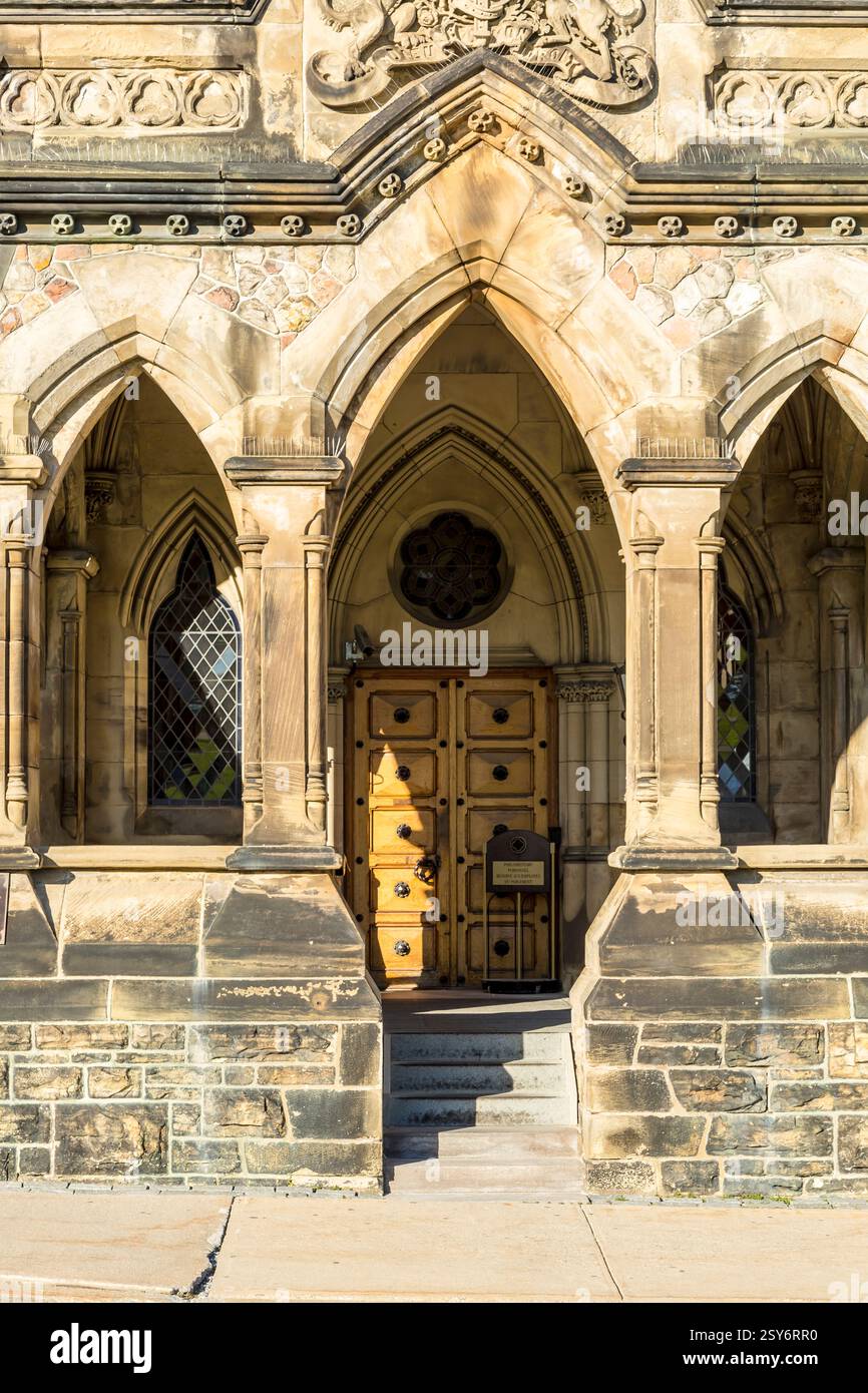 Building with a large archway and a door. The door is brown and has a ...