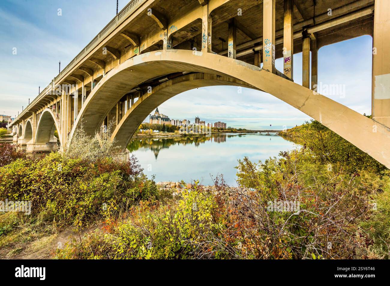 Bridge over a river with a green bush on the side. The bridge is made ...