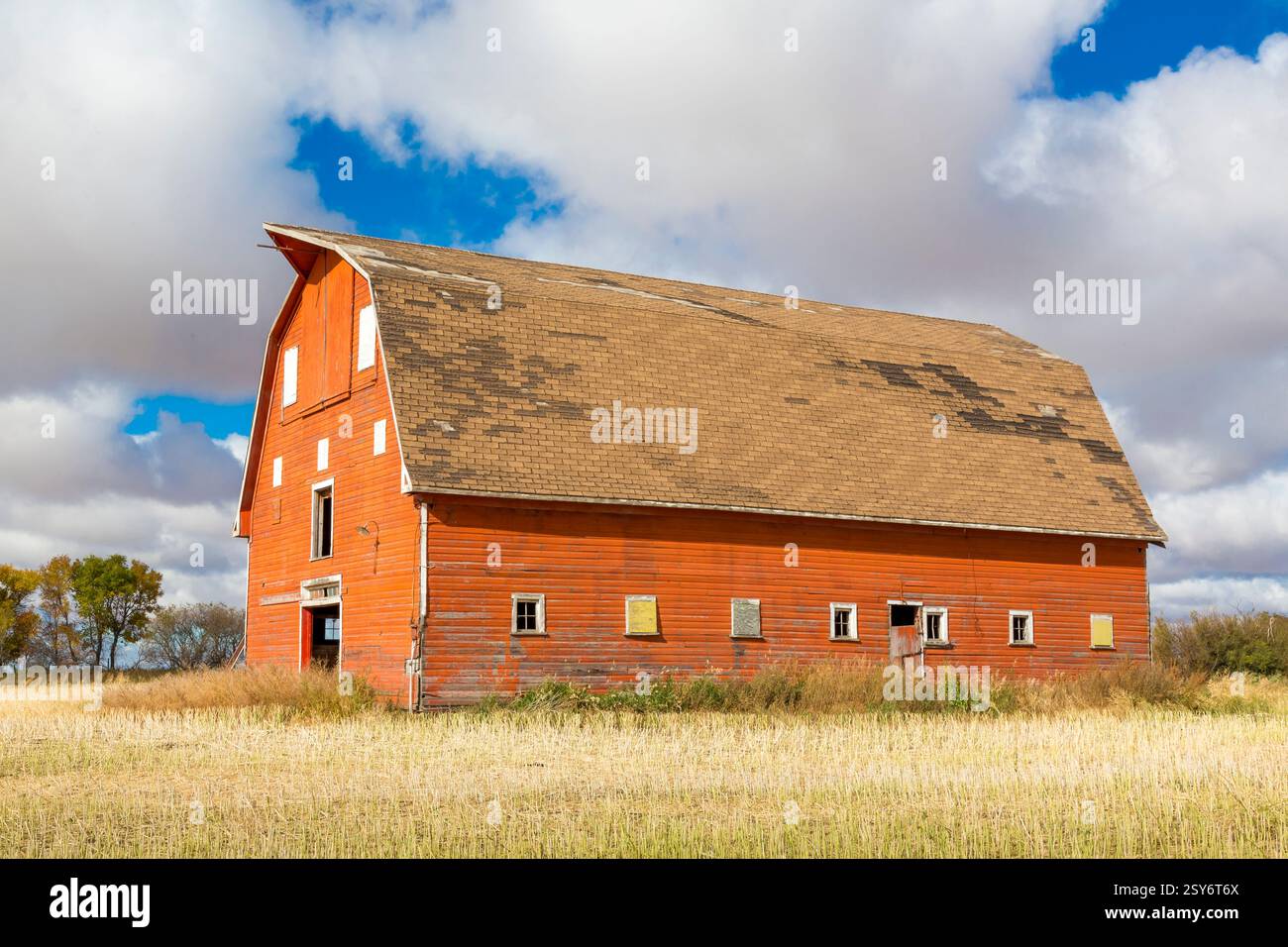 Red barn with a slanted roof. The barn is empty and has a lot of ...
