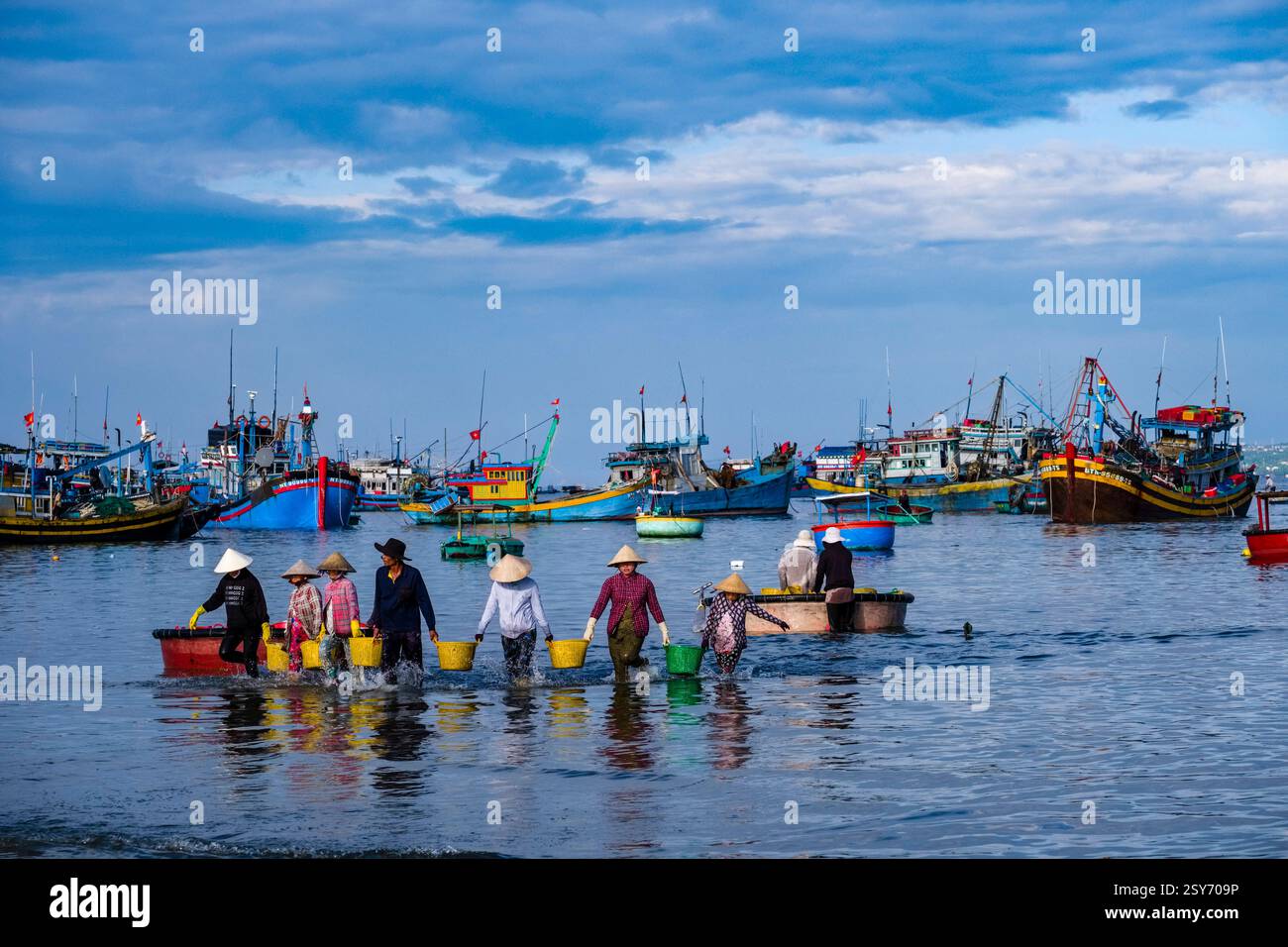 People carrying freshly caught fish in baskets to the beach at Mui Ne ...