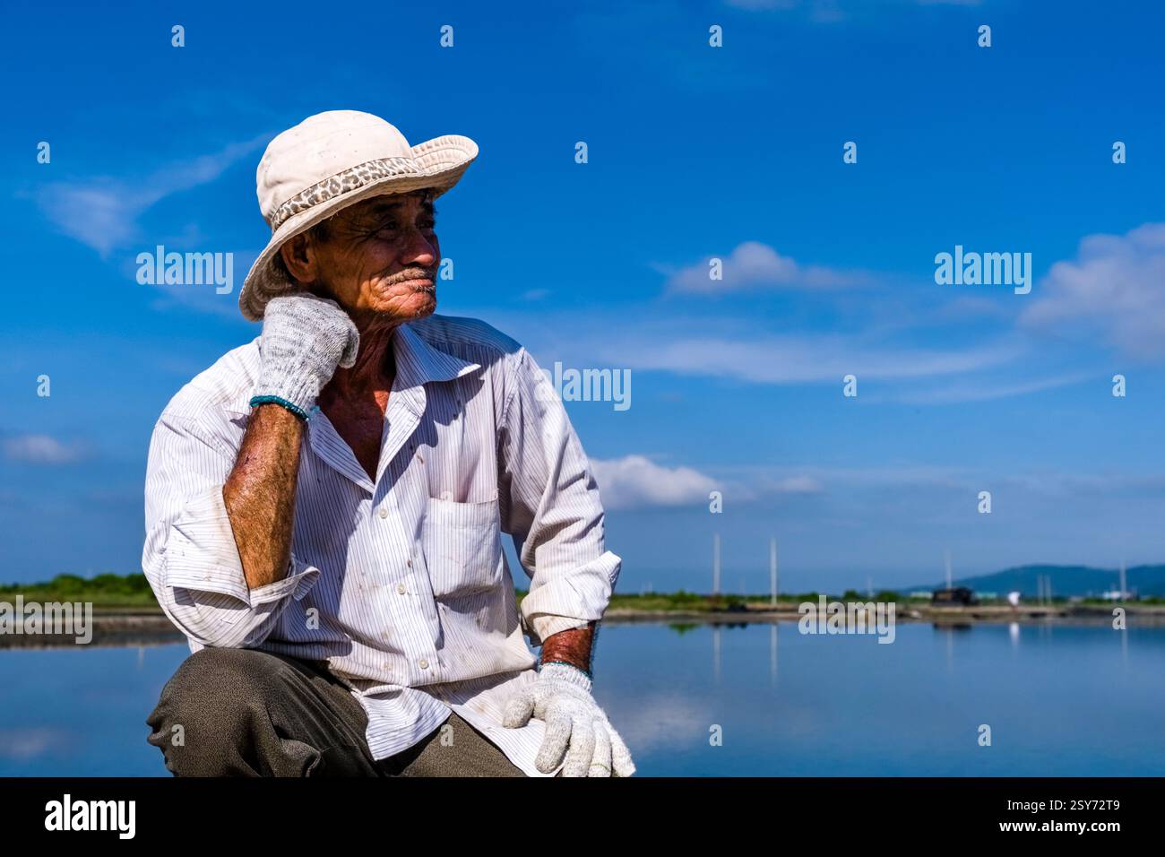 A man sits and looks out over the Long Dien salt field near Ba Ria, one ...