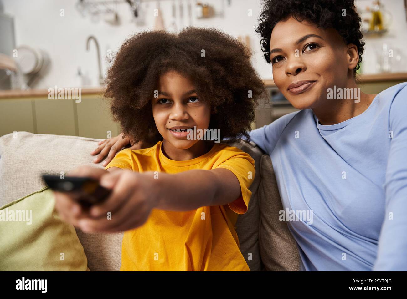 Two family members share a joyful moment on the couch while watching ...