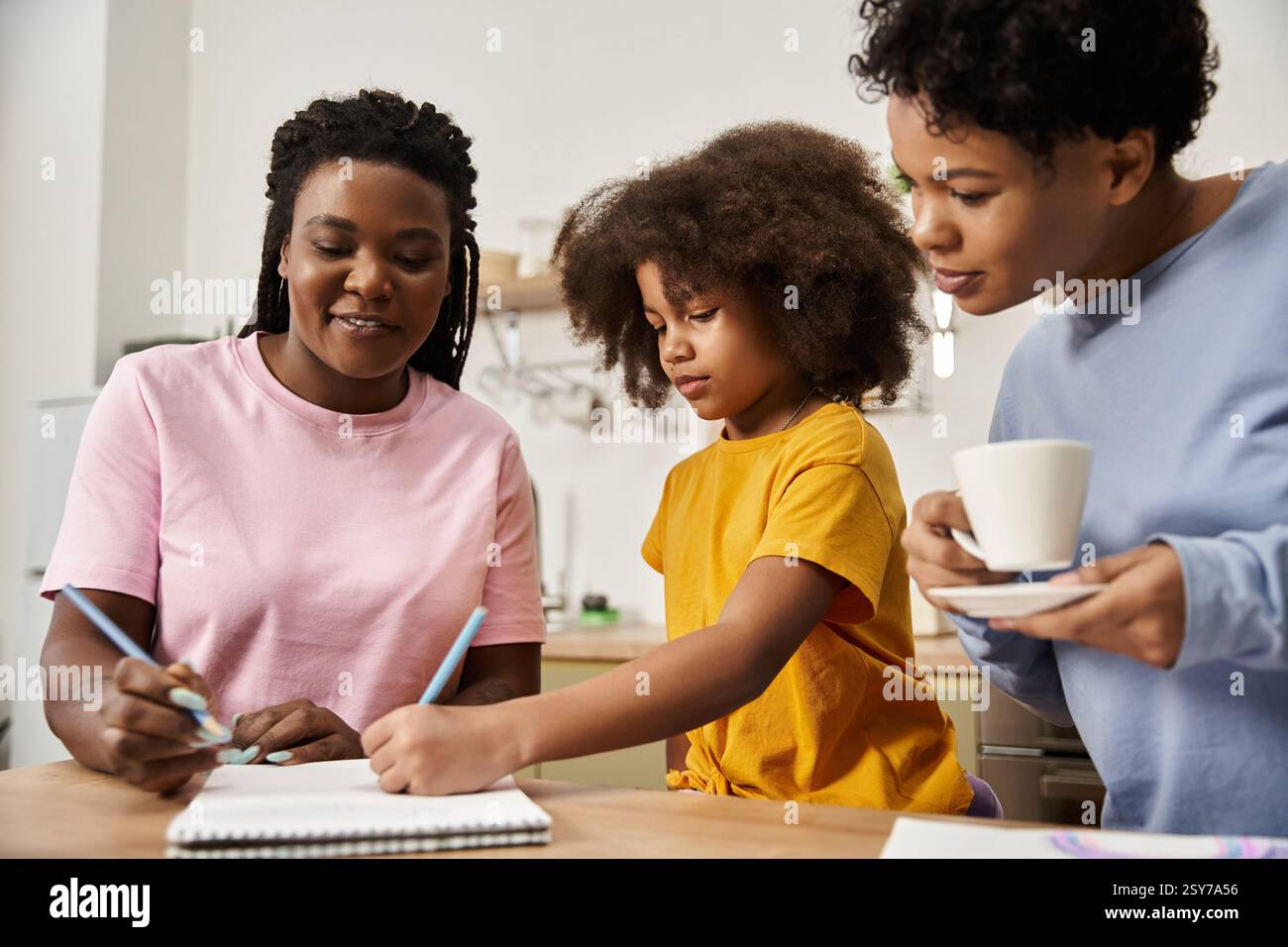 Three family members share joyful moments while drawing and sipping tea ...
