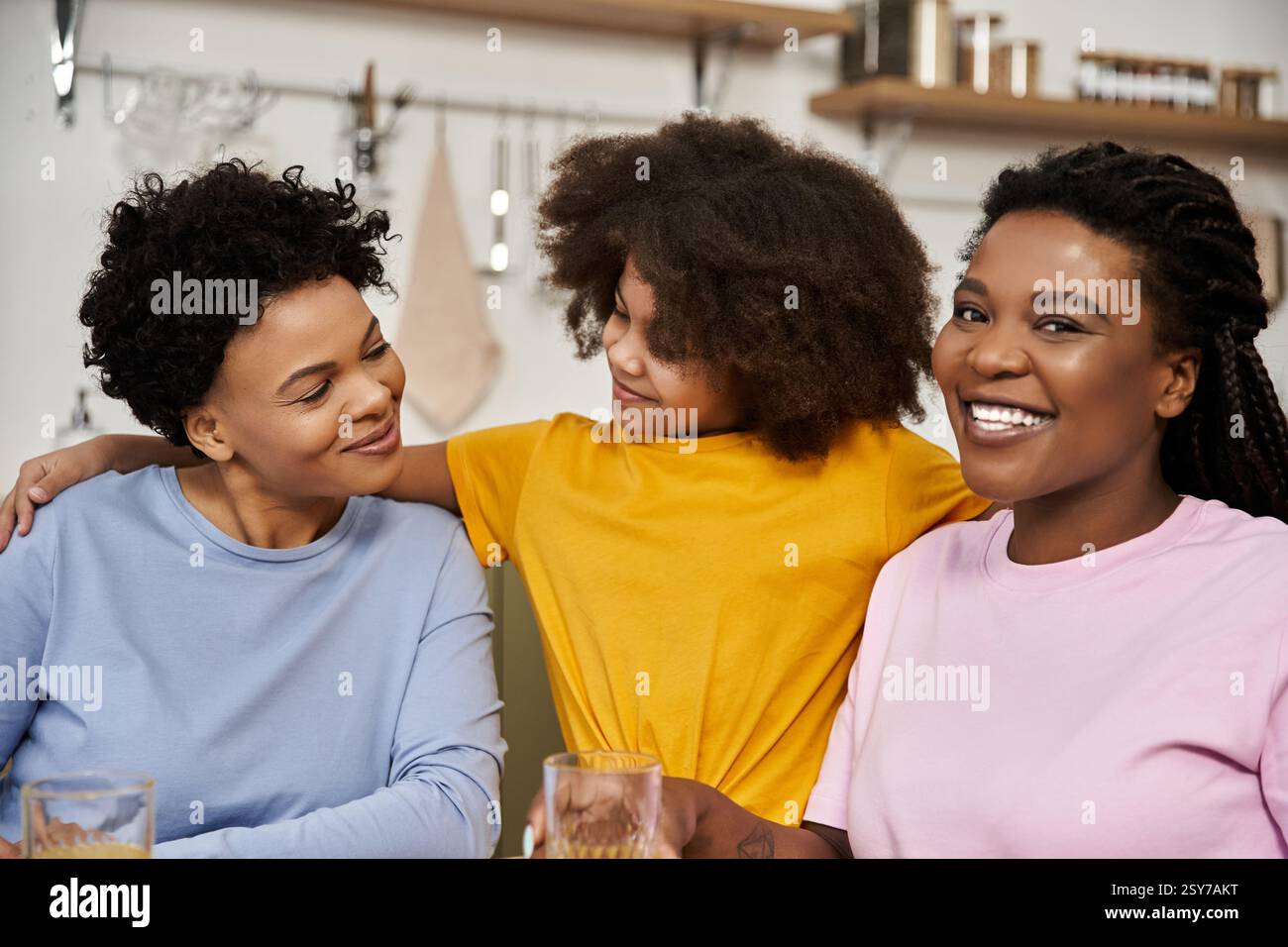 A young daughter smiles between two mothers, sharing joy during family ...