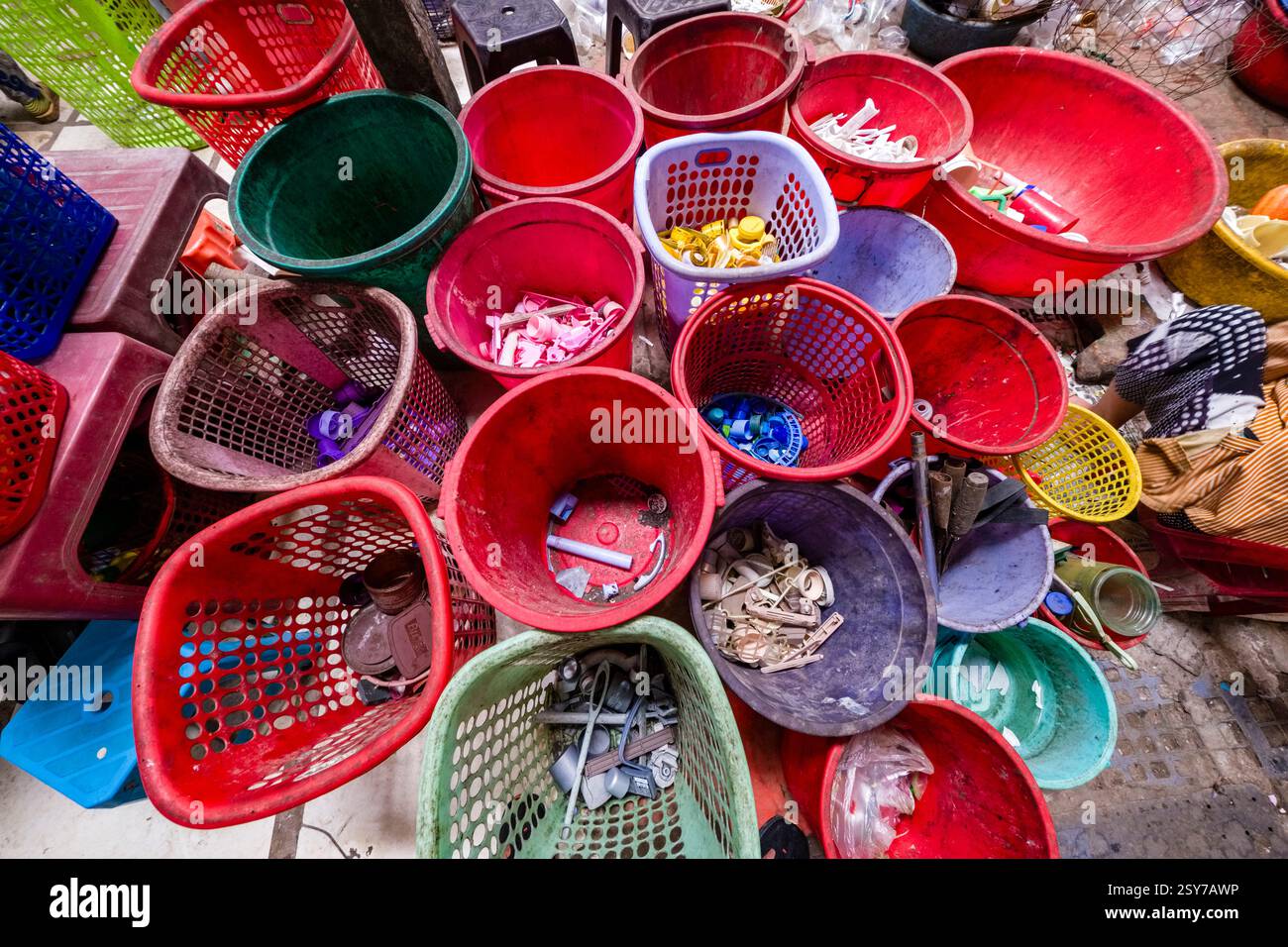 Plastic waste in buckets and baskets, sorted by local women in a hall ...