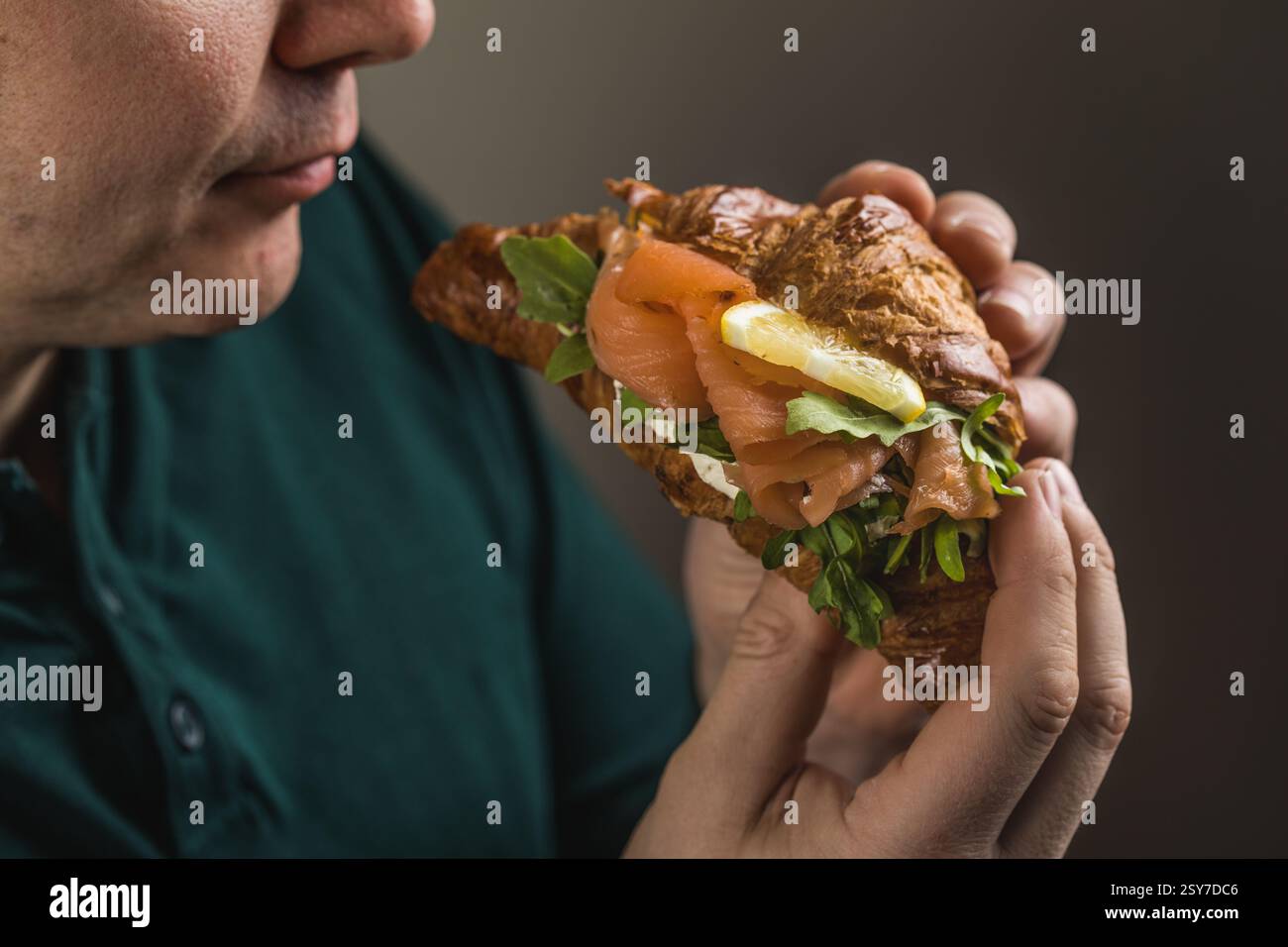 Portrait of young man eating a healthy sandwich with smoked salmon ...