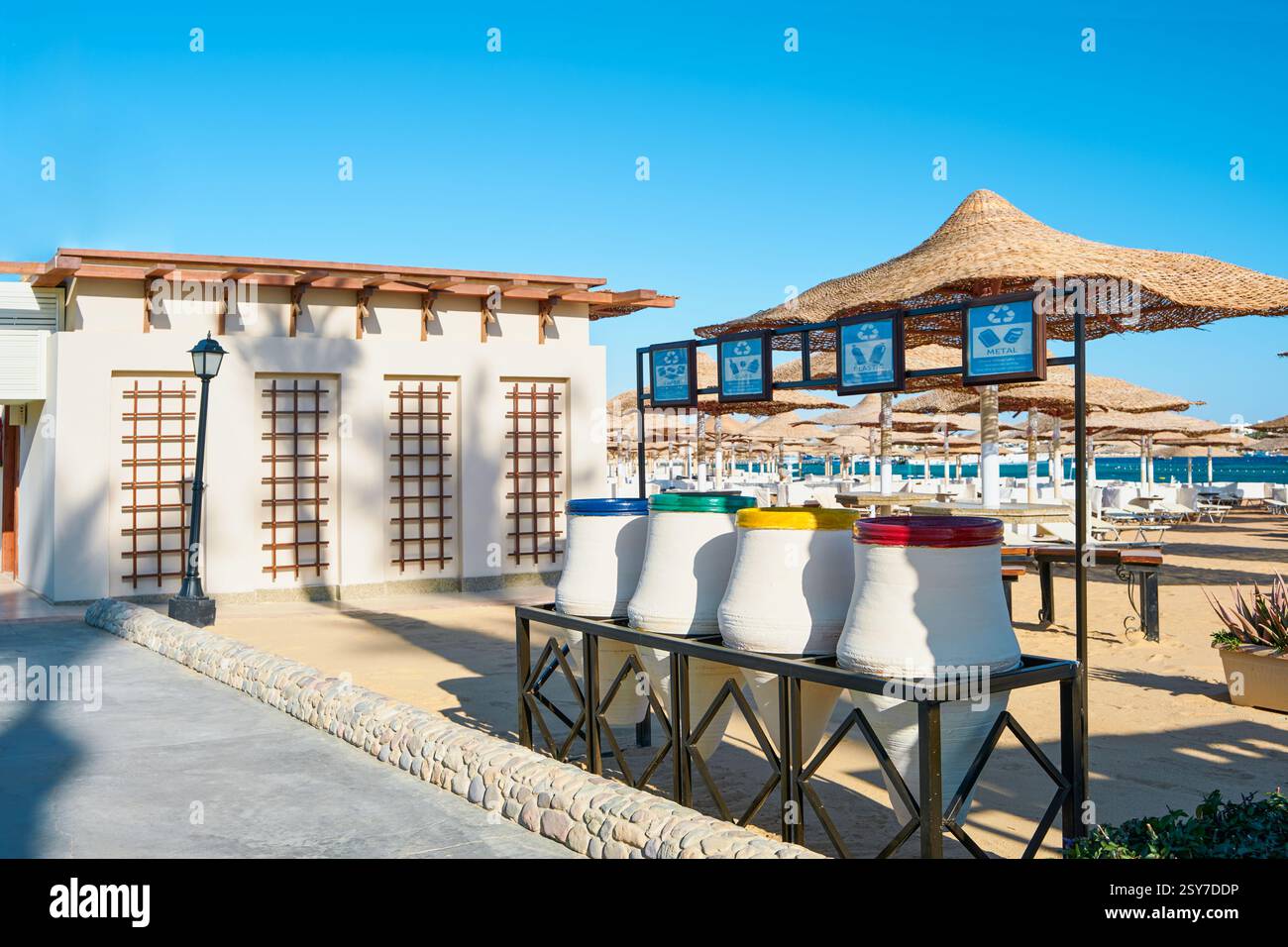Colorful clay recycling bins on beach. Containers, trash bins for ...