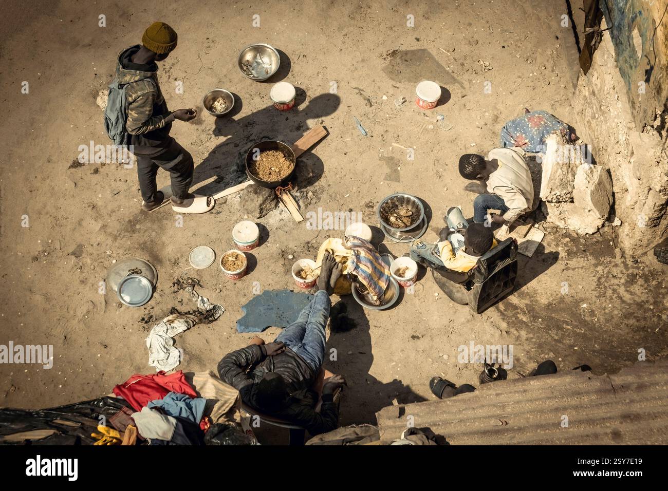Top view of the poor family cooking food in the house yard on the fire ...