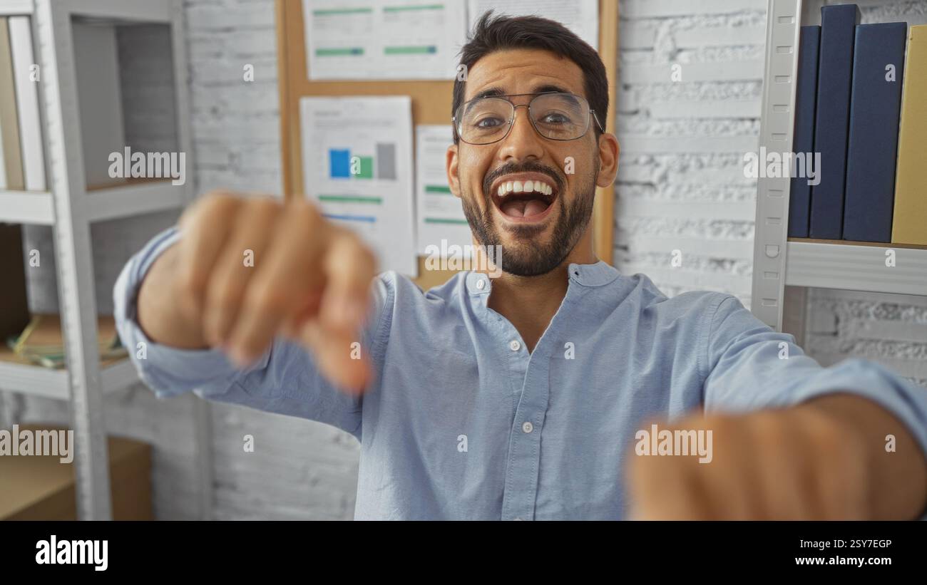 Young man smiling in an office setting with charts on the wall and ...