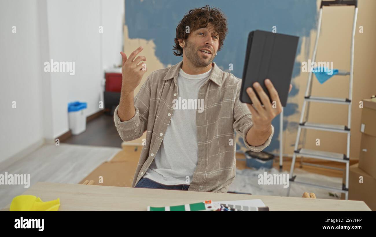 Young handsome man in new home interior taking video call on tablet ...