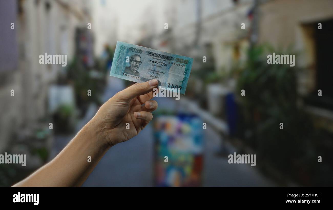 Man holding bangladeshi taka banknote outdoors on a city street ...