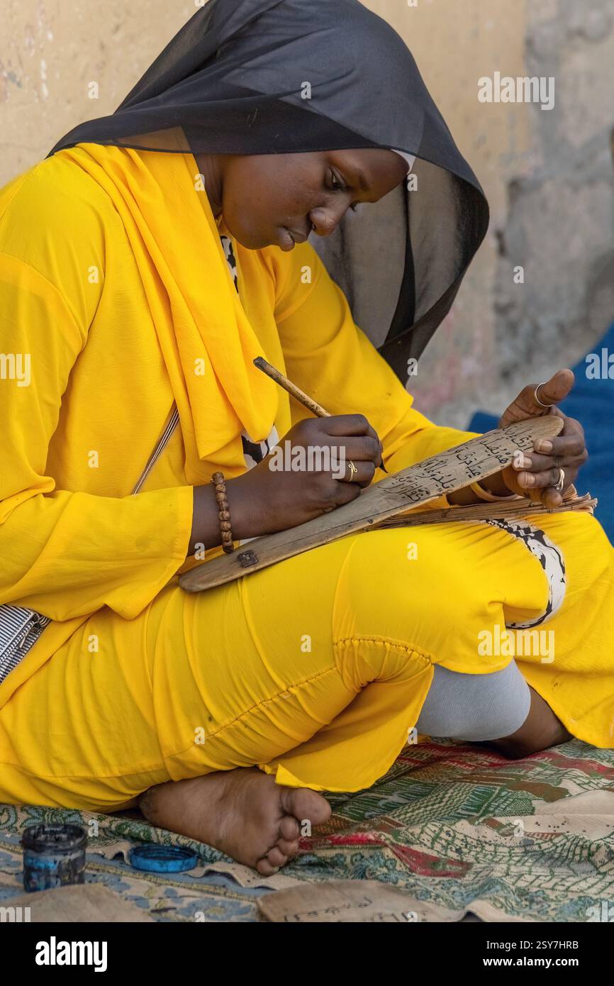 Young african woman wearing traditional clothes writing islamic holy ...
