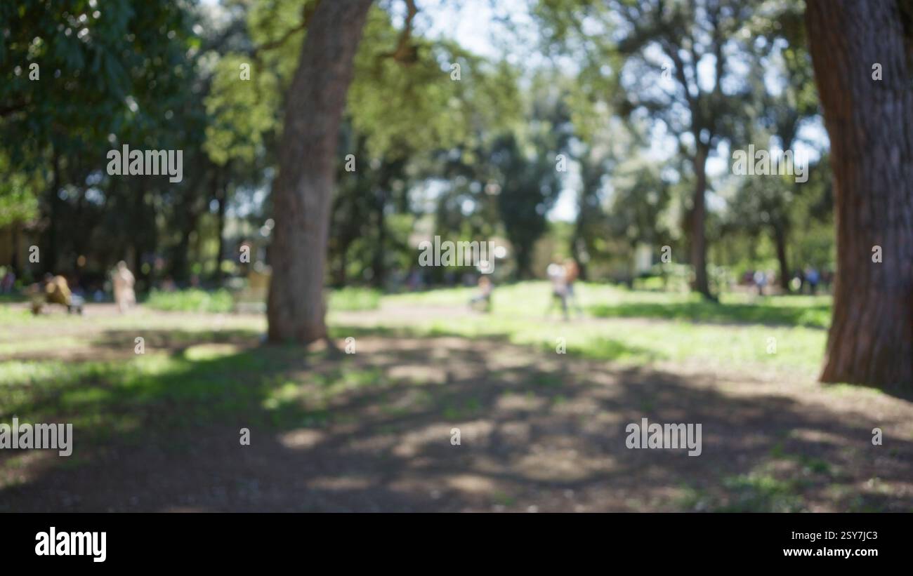 Blurred view of villa borghese gardens in rome, with trees and people ...