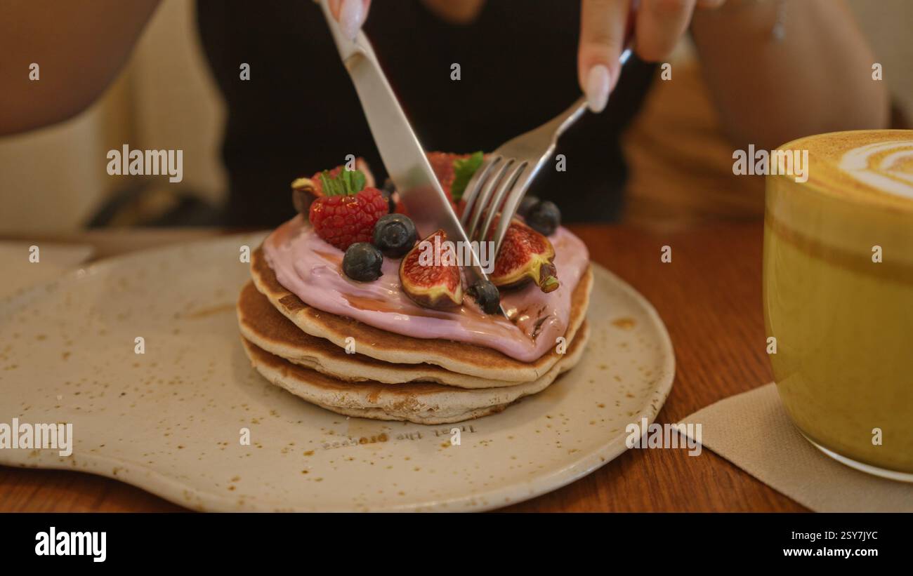 Woman enjoying pancakes with fruit at a cozy restaurant table while ...