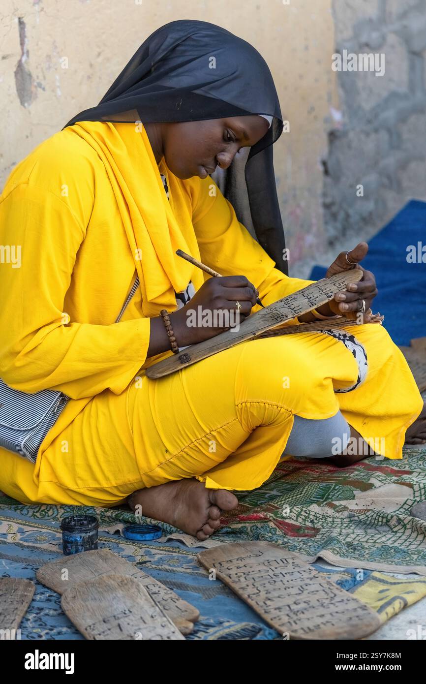 Young african woman wearing traditional clothes writing islamic holy ...