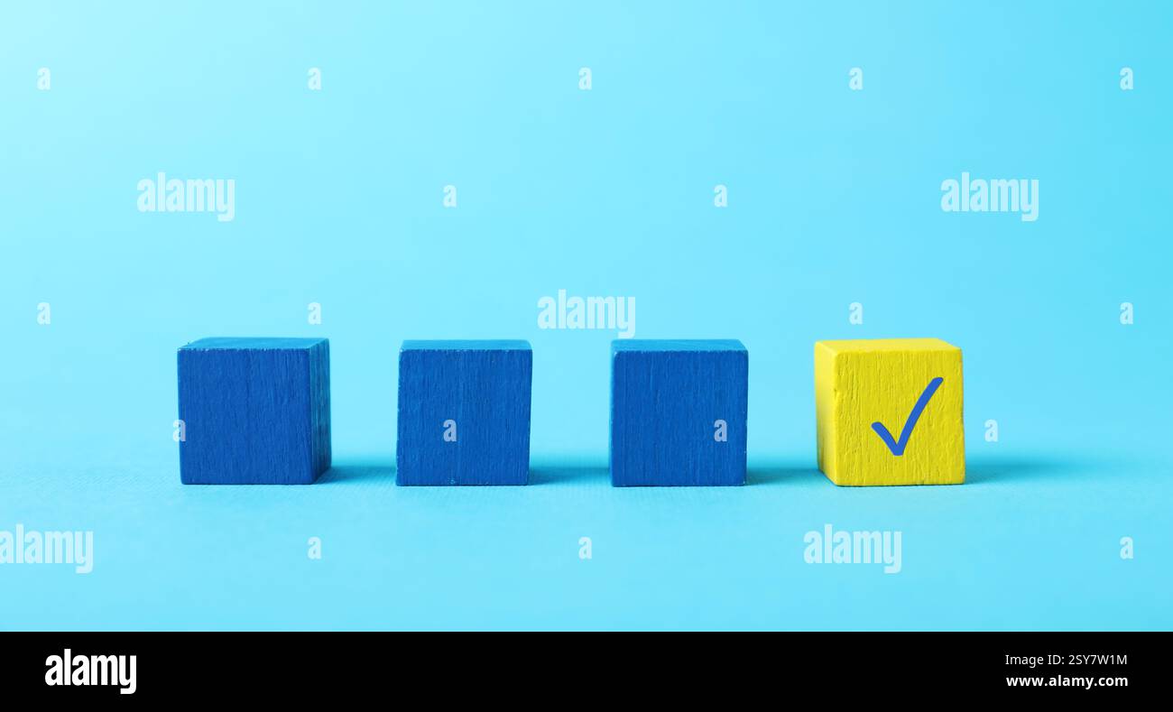 One yellow cube with check mark among others on light blue background Stock Photo - Alamy