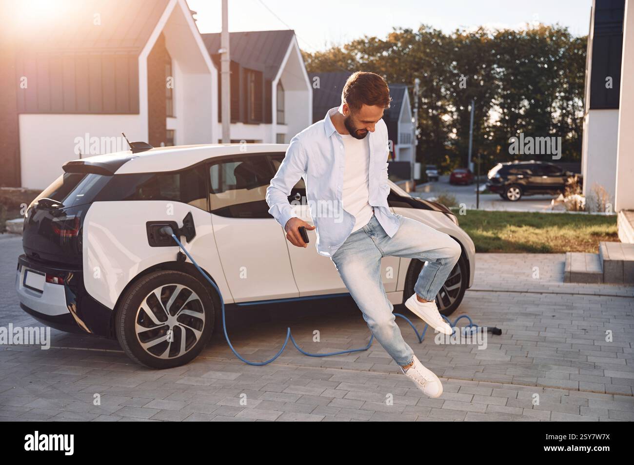 Jumping and having fun. Charging the vehicle. Young stylish man is with ...