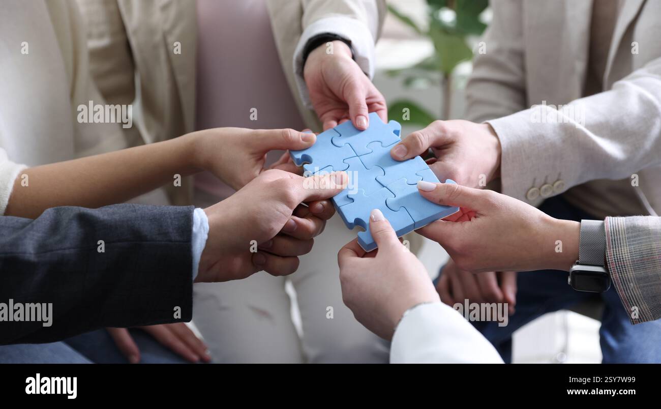 Unity concept. People putting puzzle pieces together indoors, closeup ...