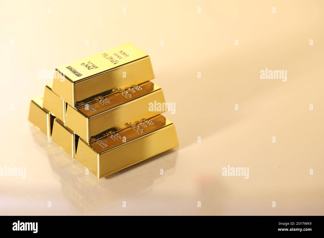 Many stacked gold bars on beige background, closeup. Space for text ...