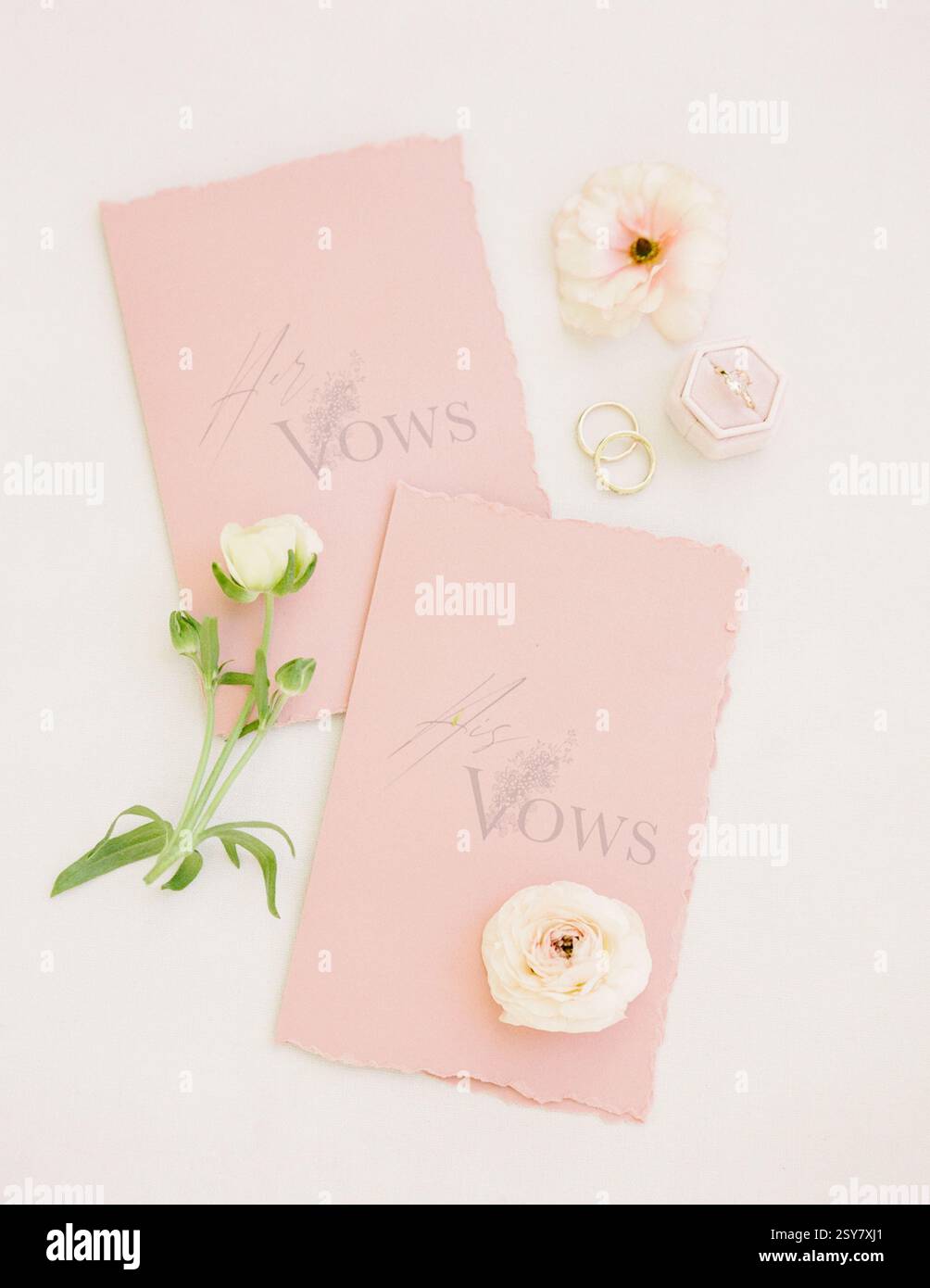 Delicate pink vow cards with floral accents and rings on a neutral ...
