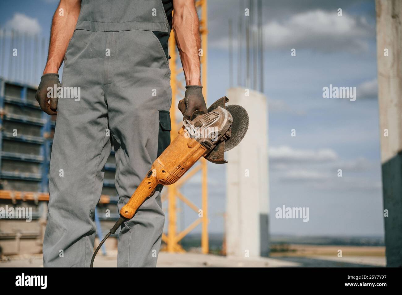 Holding grinding machine. Man in uniform is working on the construction ...