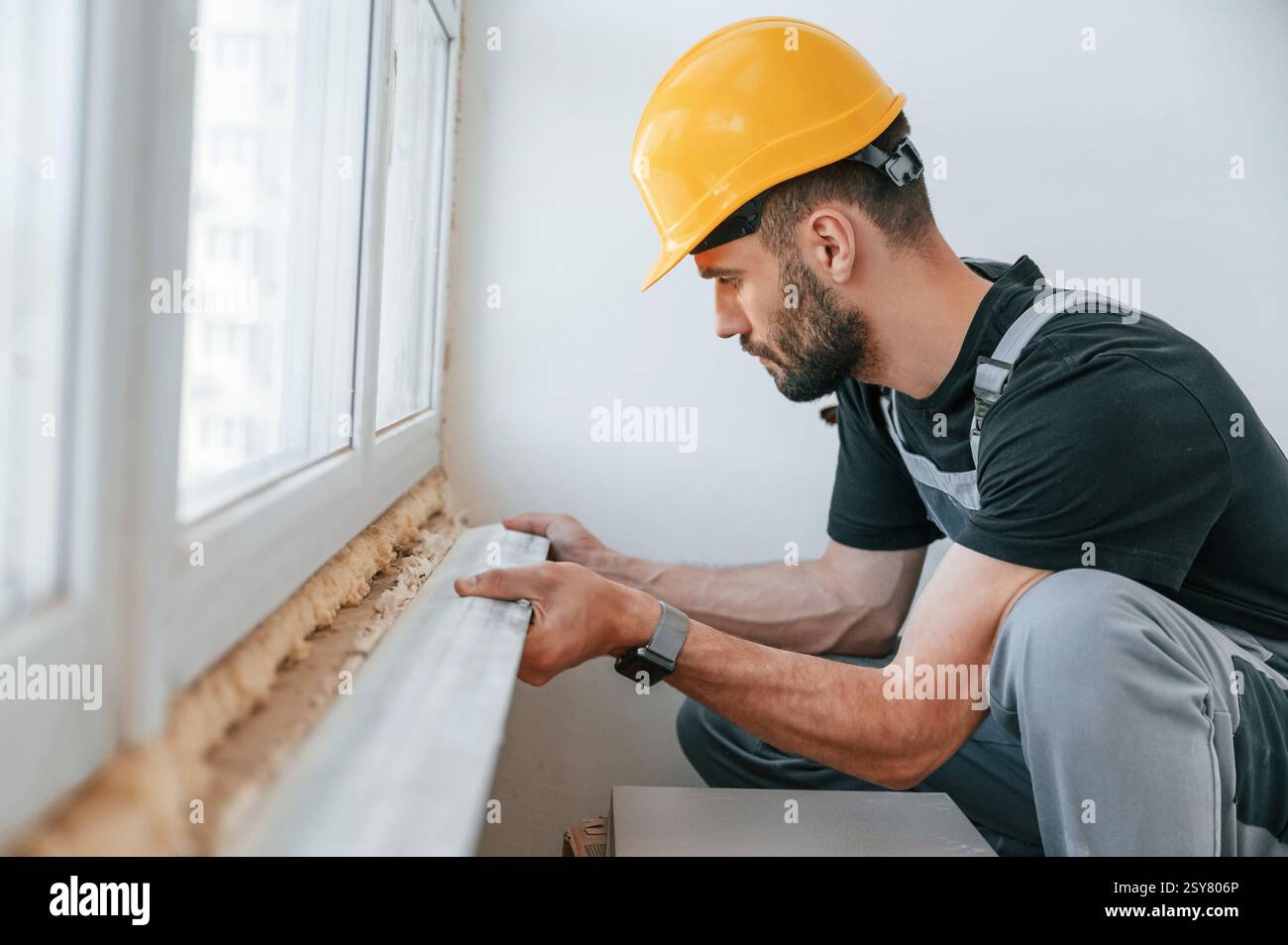 Installing a window sill. The man is making repairs in the apartment ...