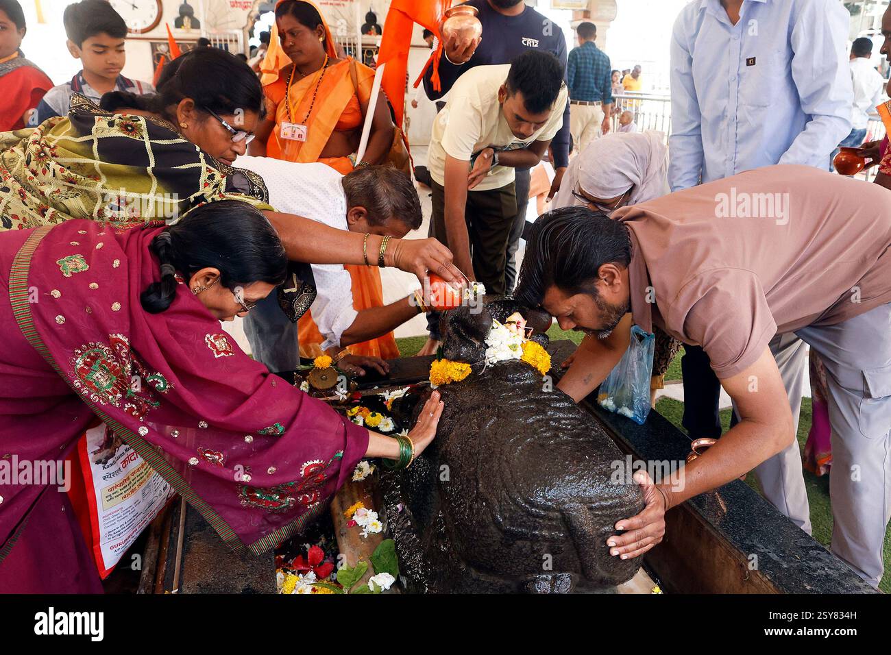 Devotees pour water over a statue of Nandi at the Shri Raj Rajeshwar ...