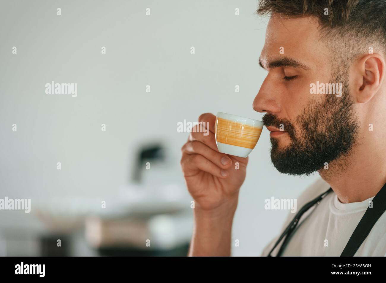 Side view. Tasting delicious coffee. Cafe worker in white shirt and ...