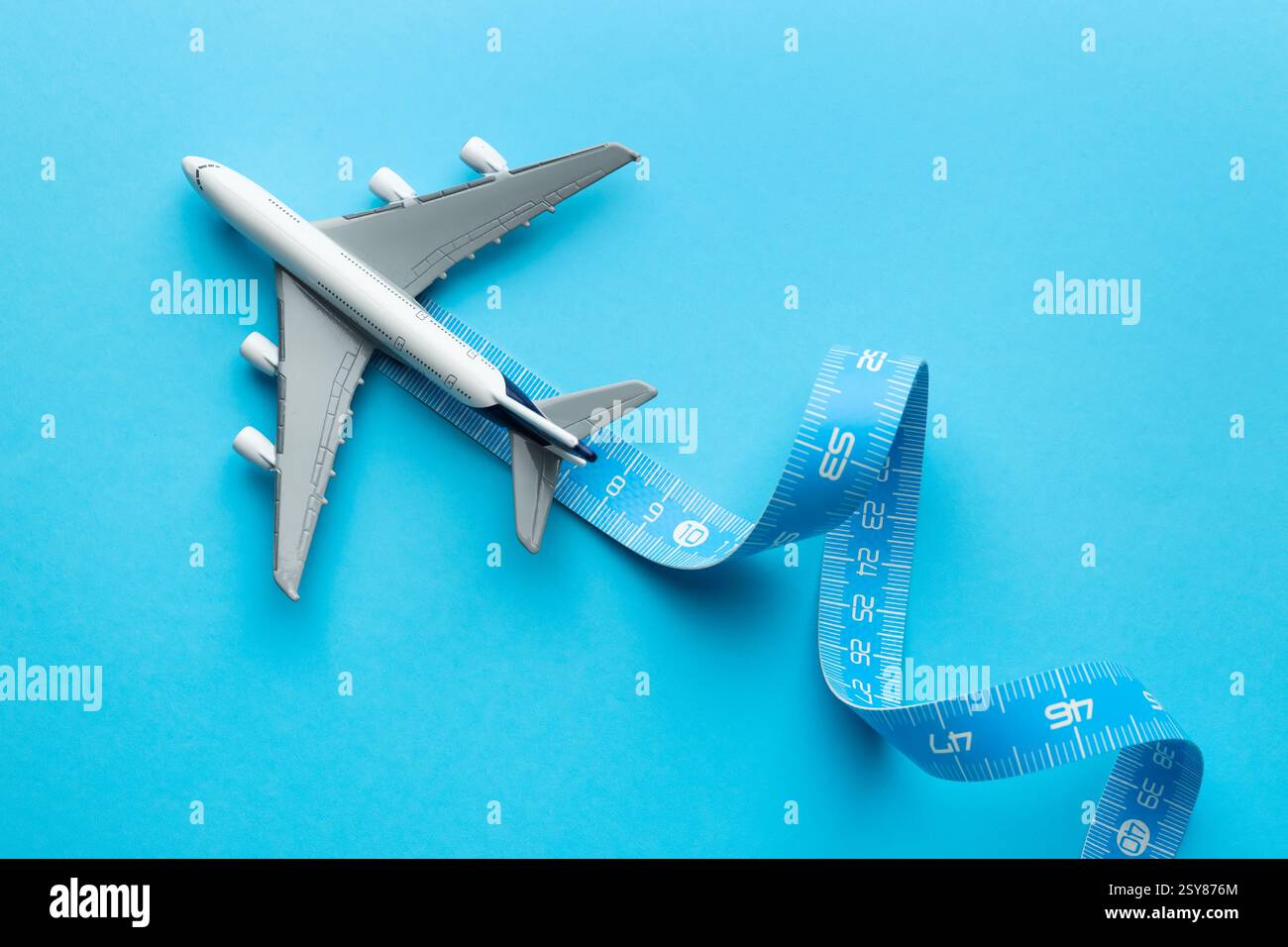 Plane model and measuring tape as flight path on light blue background ...