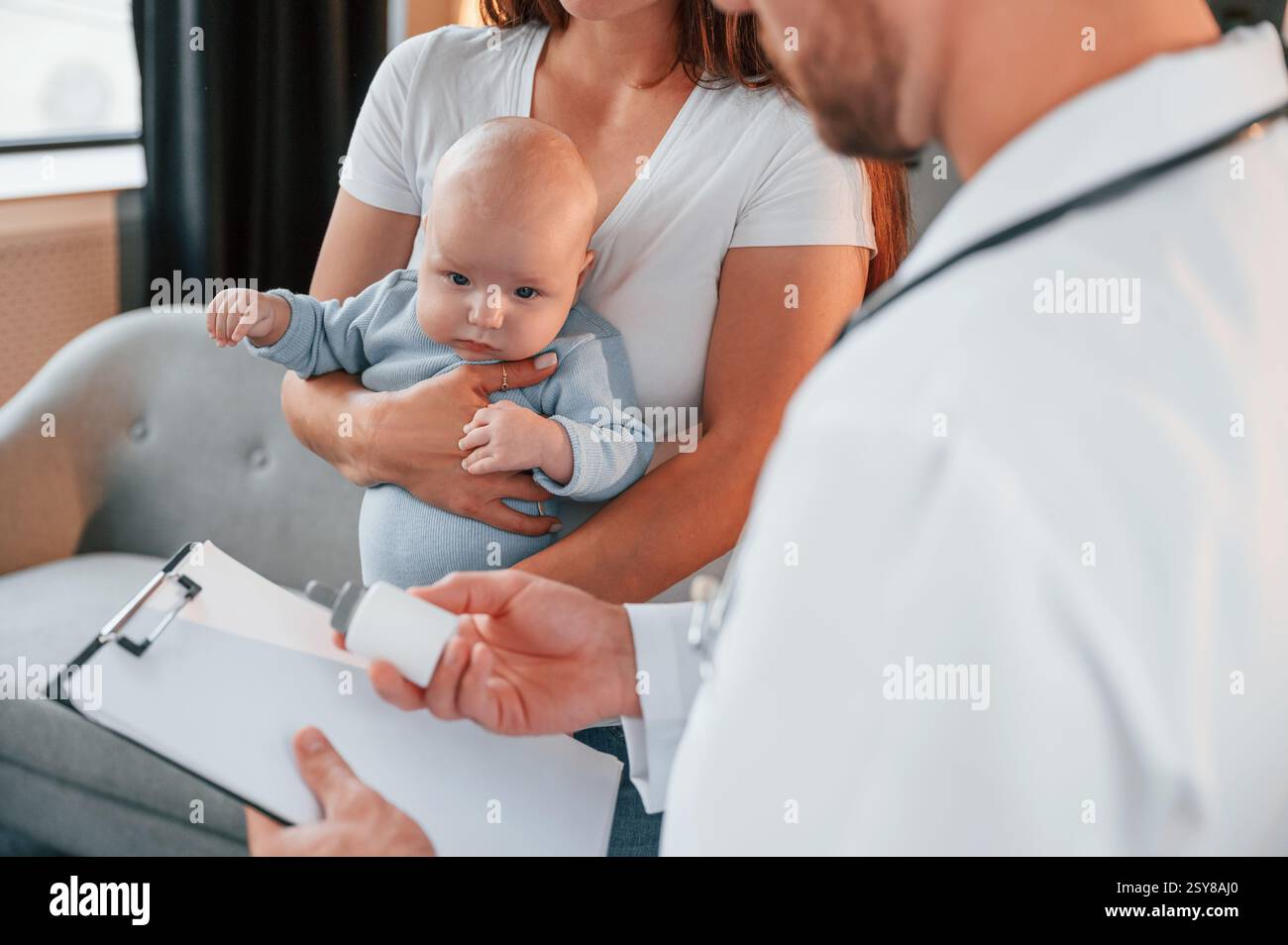 With a prescription. Male doctor is taking care of woman's newborn baby ...