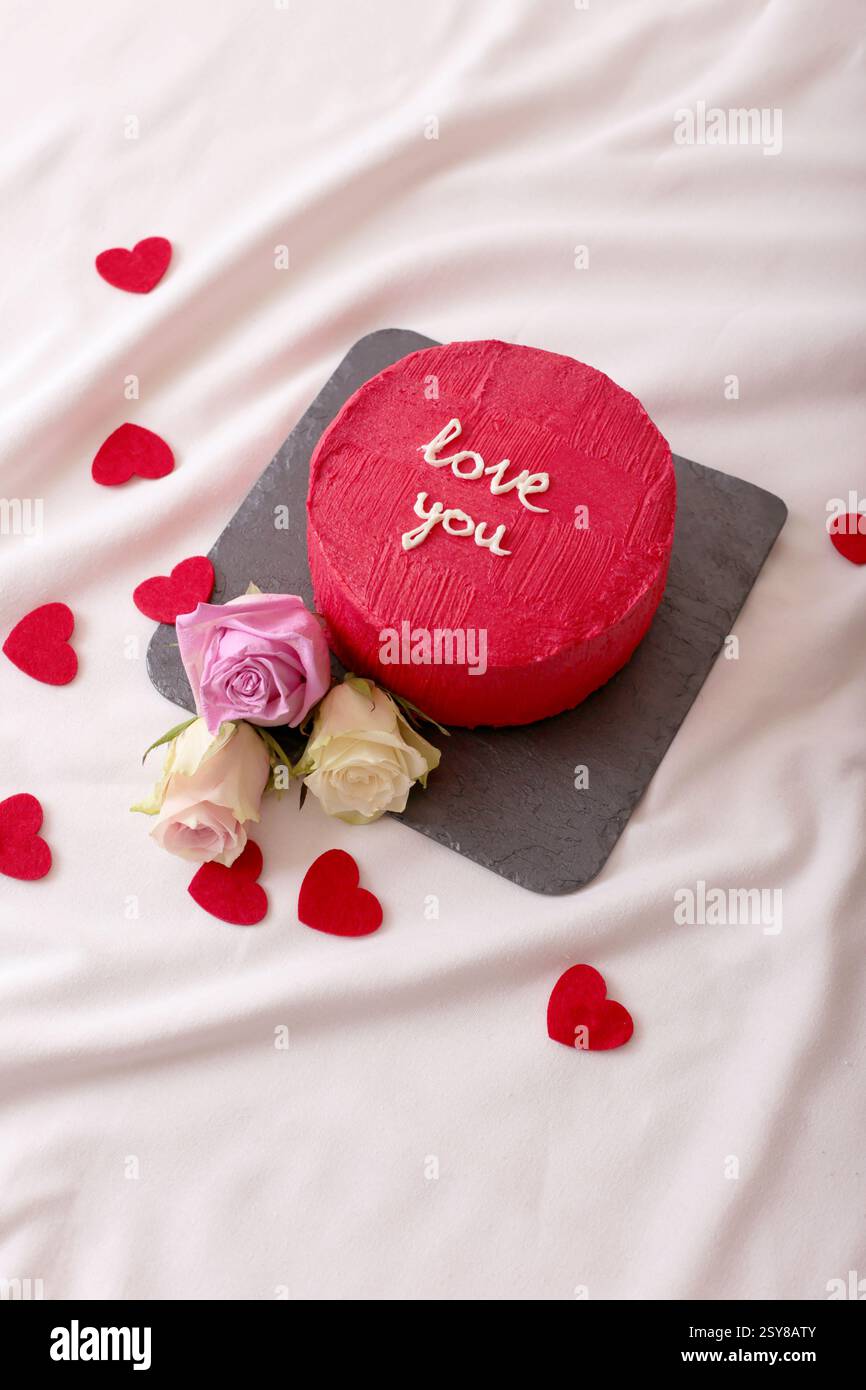 Red cake with 'love you' message and roses on white fabric with heart ...