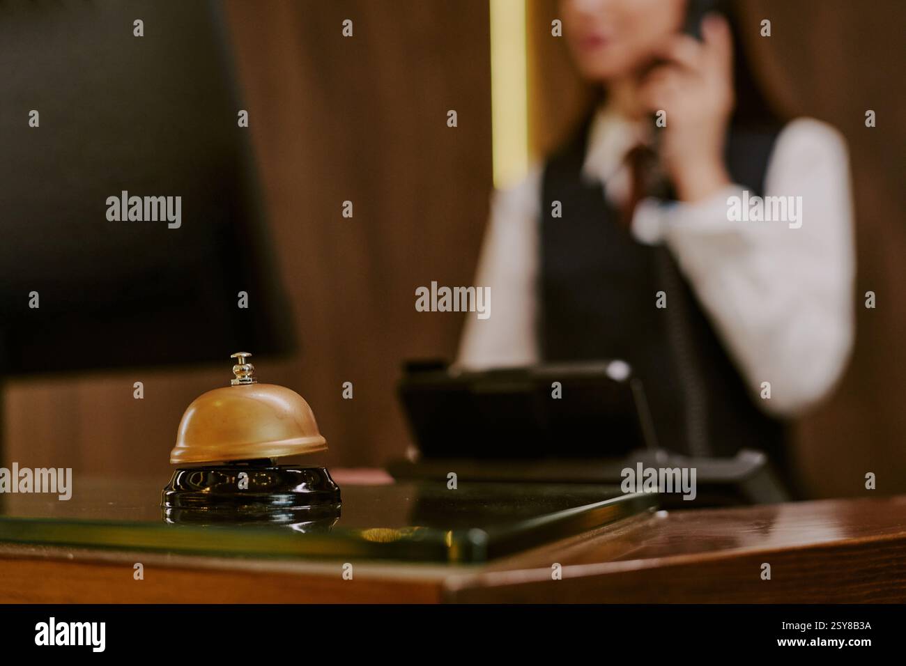Medium close up of golden bell on polished table in hotel lobby ...