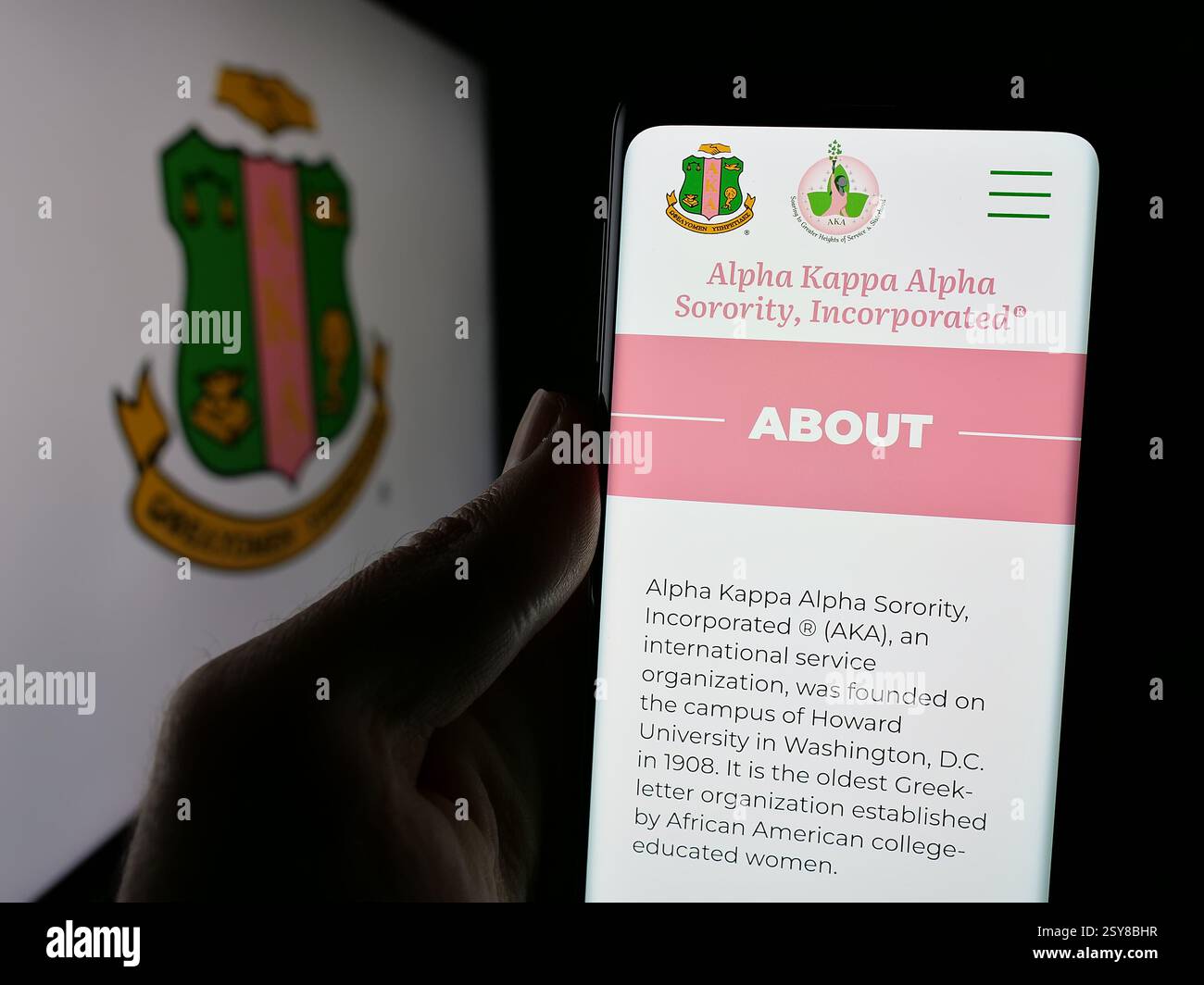 In this photo illustration, a person is holding a cellphone with the webpage of US Alpha Kappa ...