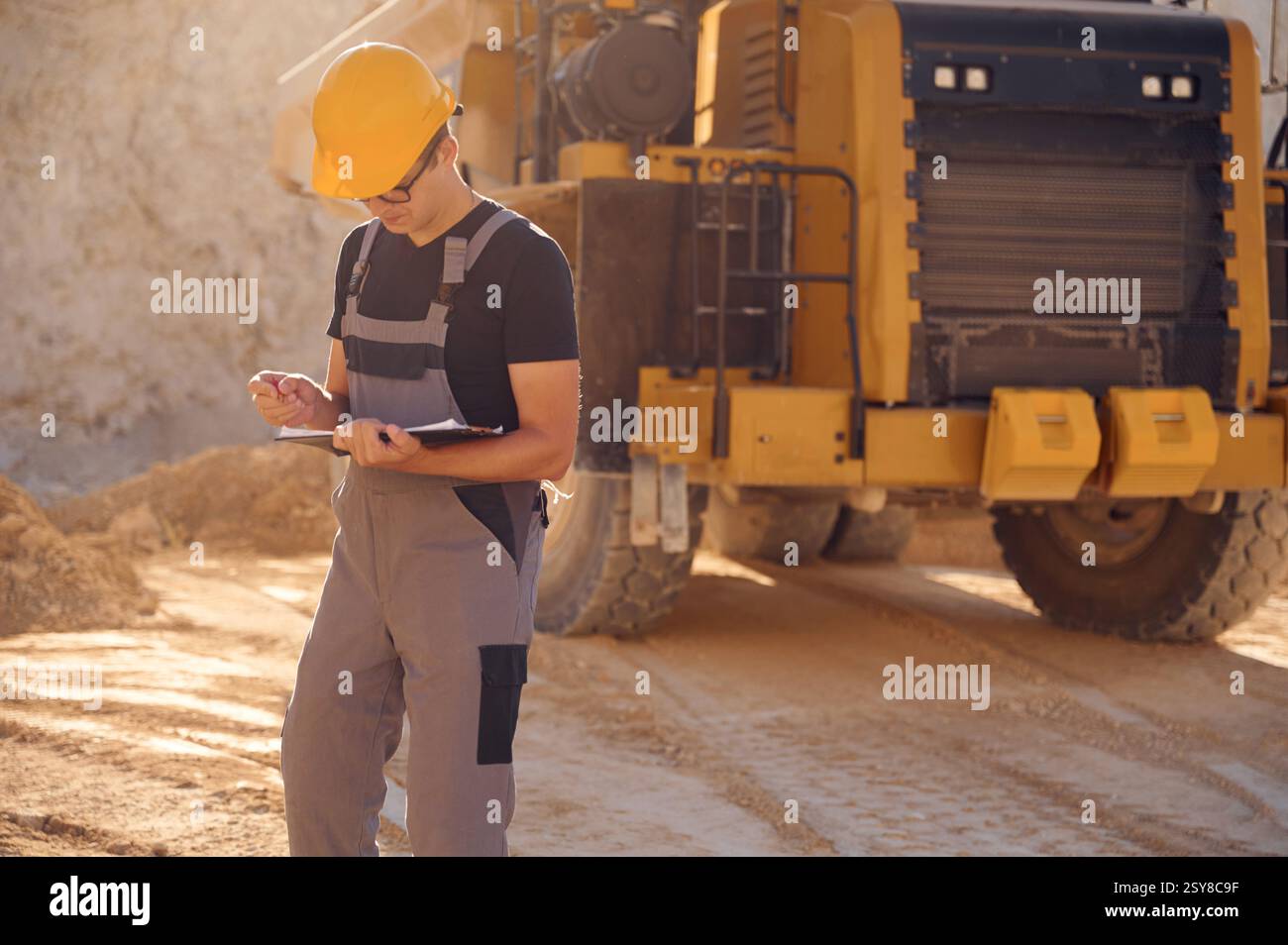 With documents near the haul truck. Man in uniform is working in the quarry at daytime Stock ...