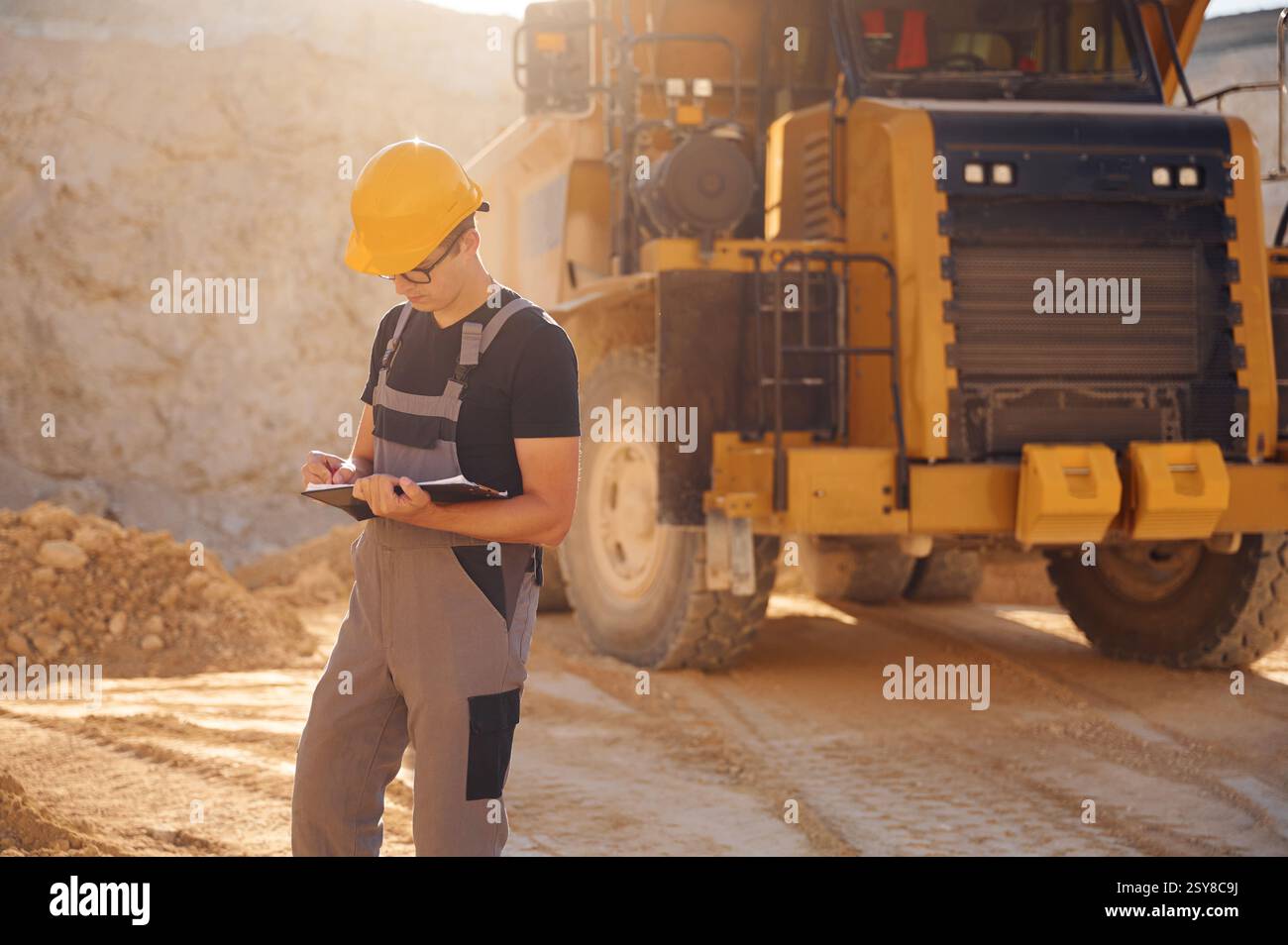 With documents near the haul truck. Man in uniform is working in the quarry at daytime Stock ...