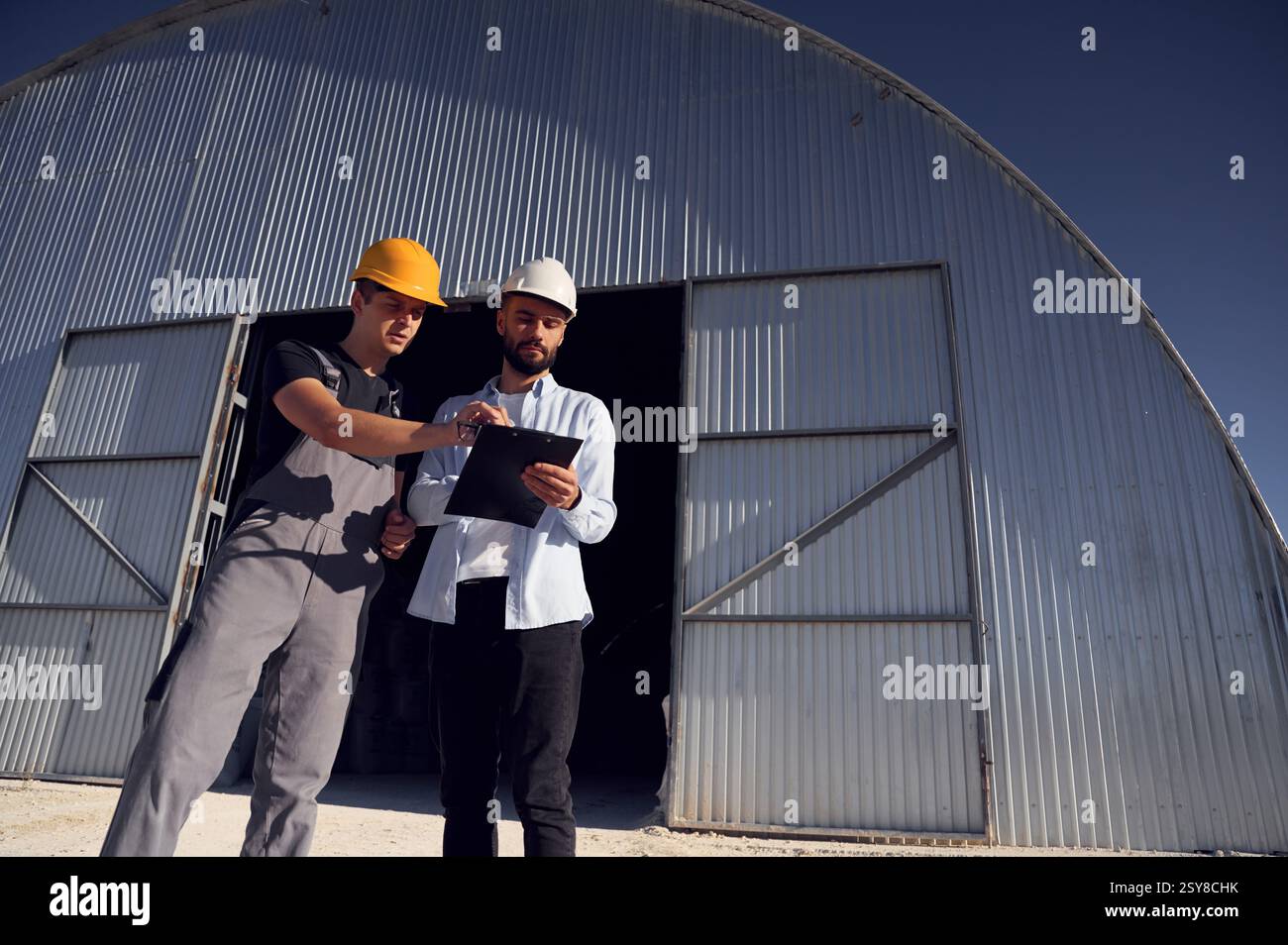 Two workers is standing against big hangar and reading the plan Stock ...