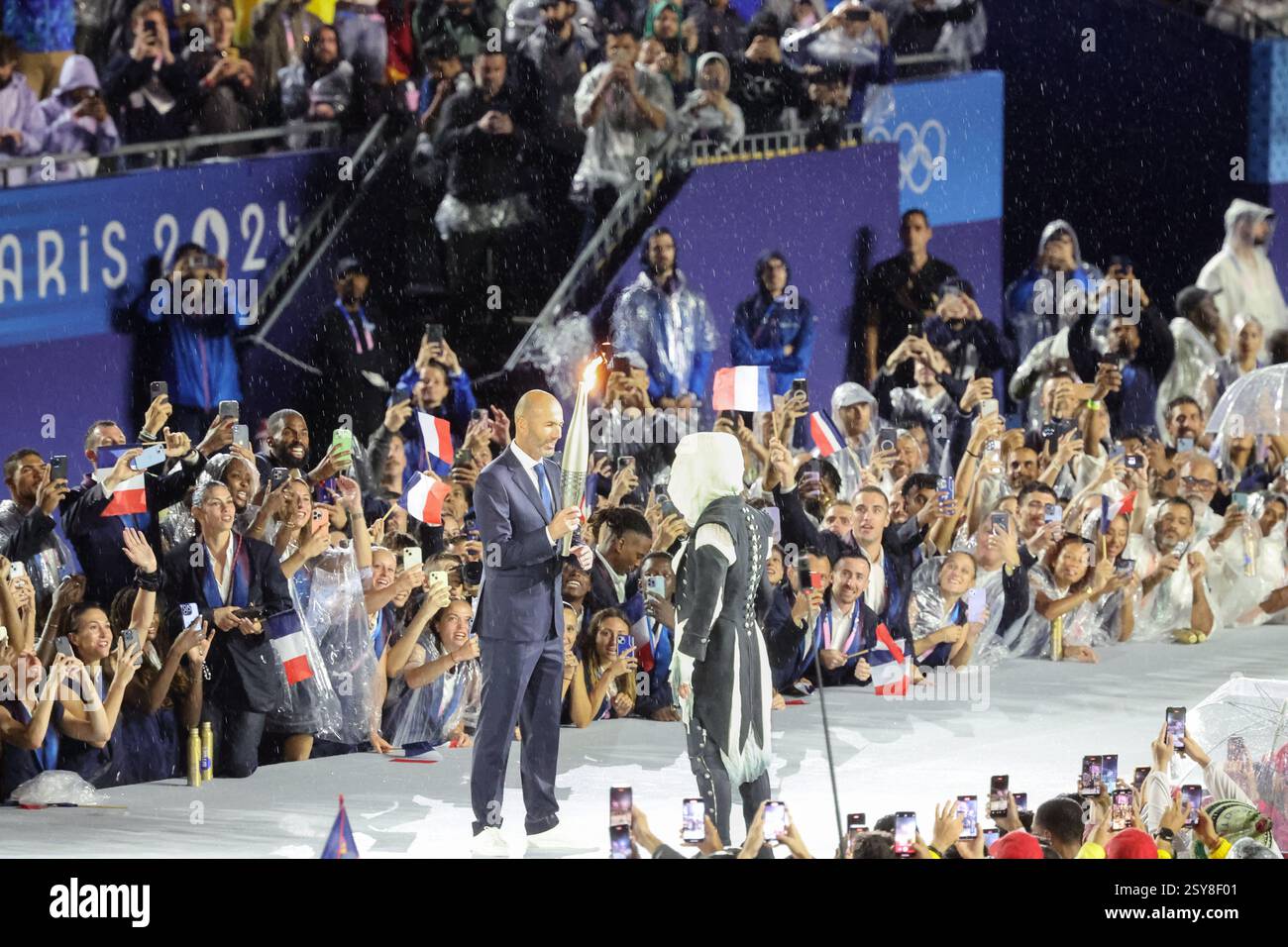 July 26th, 2024 - Paris, France: the masked torchbearer gives the ...