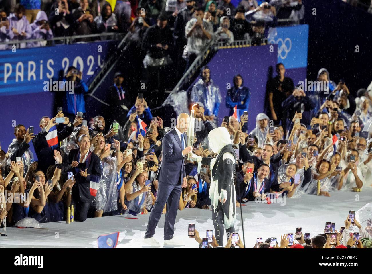 July 26th, 2024 - Paris, France: the masked torchbearer gives the ...