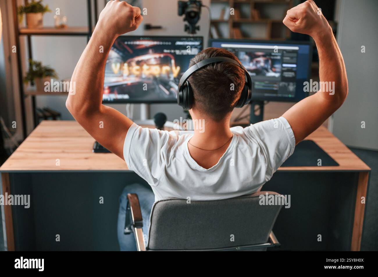 With hands up. Celebrating victory. Young man playing and streaming the ...