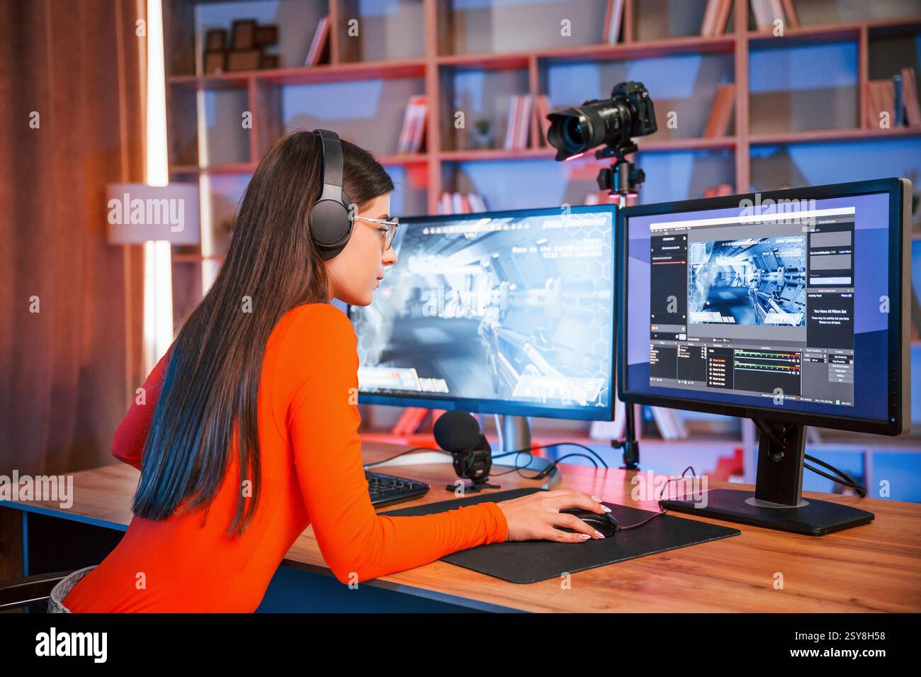 First person shooting game. Young beautiful streamer is indoors with pc ...