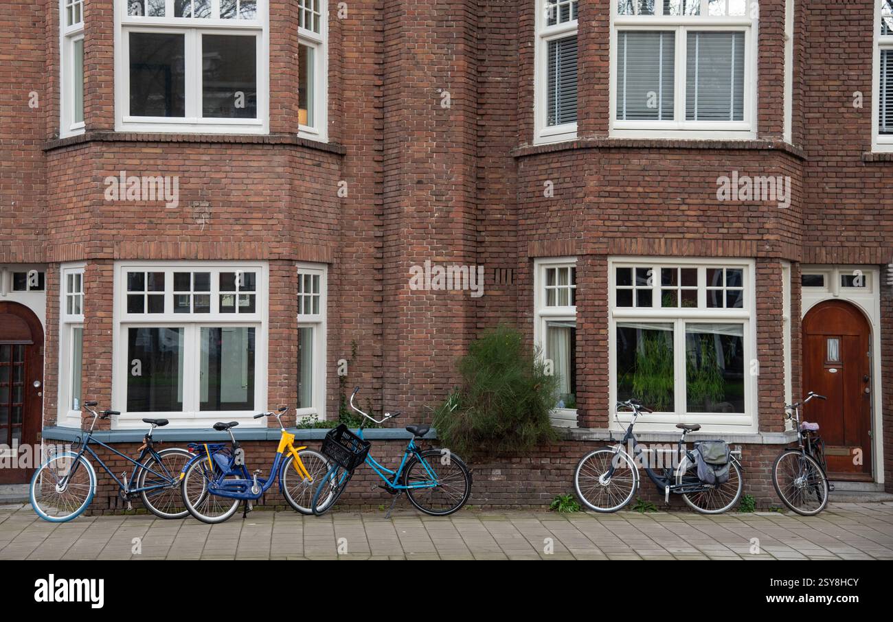 Colorful bicycles parked on the sidewalk in front of a typical dutch ...