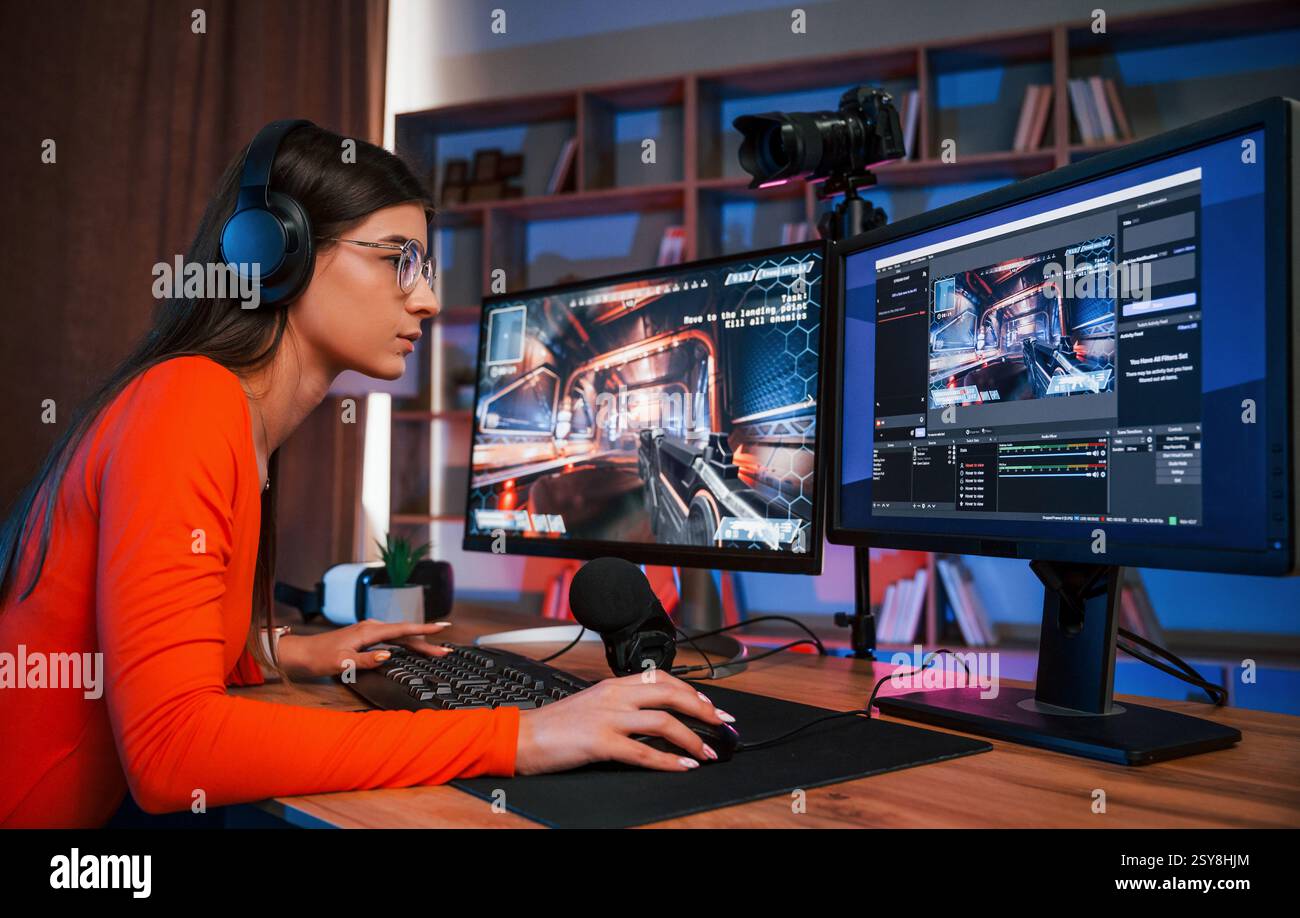 Focused on the game process. Young beautiful streamer is indoors with ...