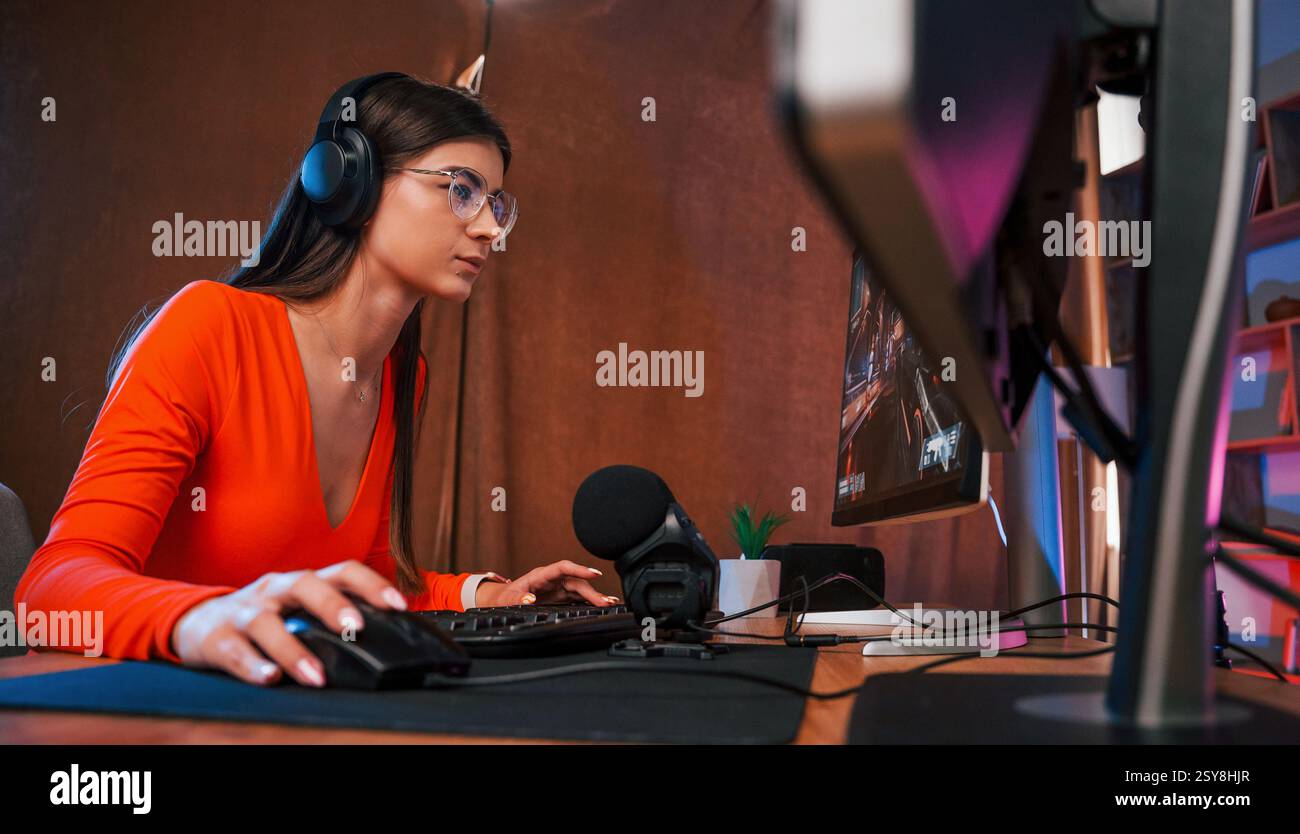 Focused on the game process. Young beautiful streamer is indoors with ...