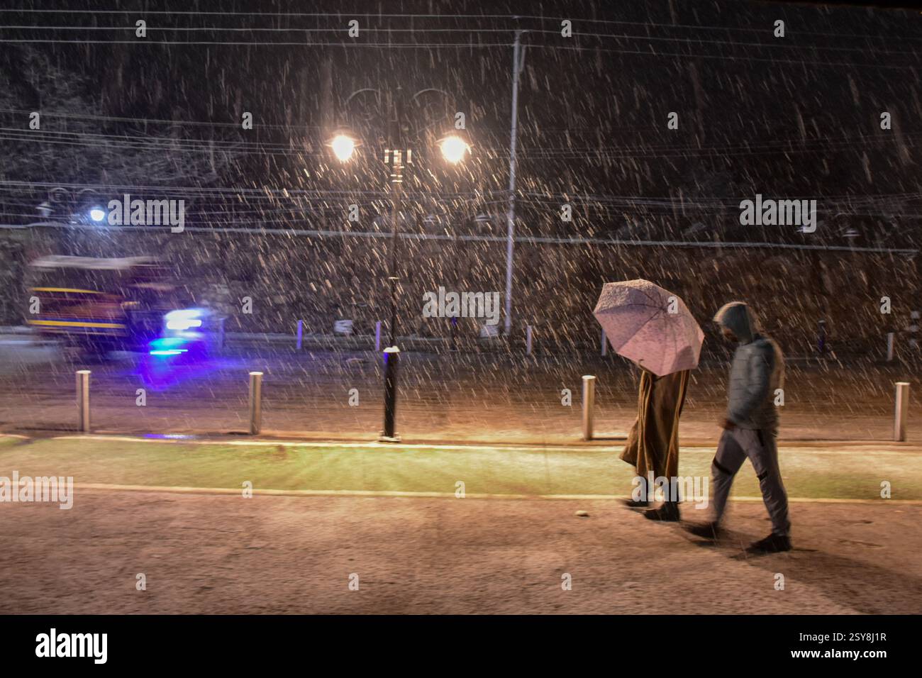 Srinagar, India. 27th Feb, 2025. Commuters walk through the snow ...