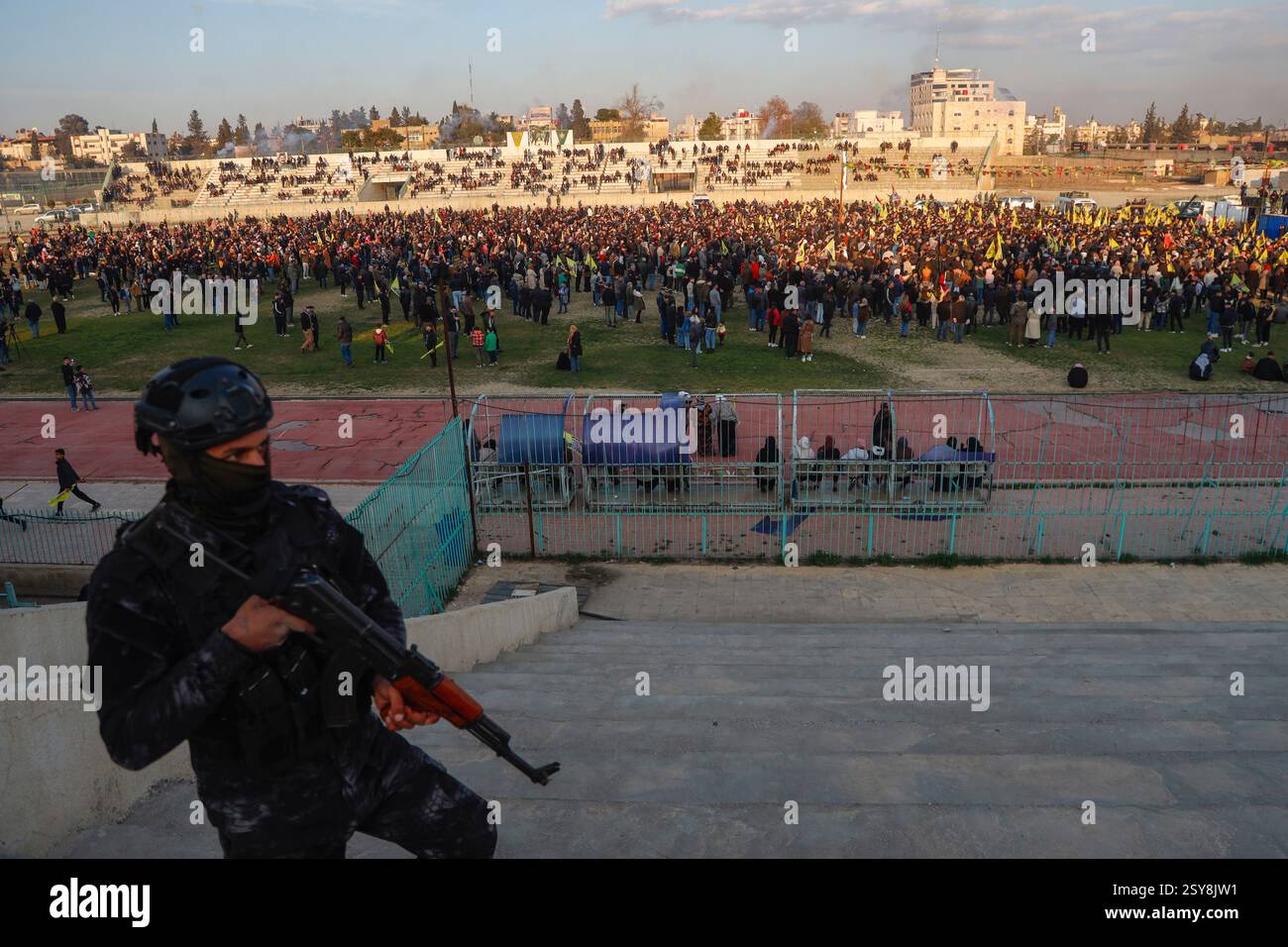 A Syrian Democratic Forces (SDF) fighter stands in guard as hundreds ...