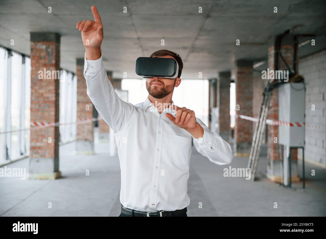 On the construction site. Man in formal clothes is playing VR game in ...
