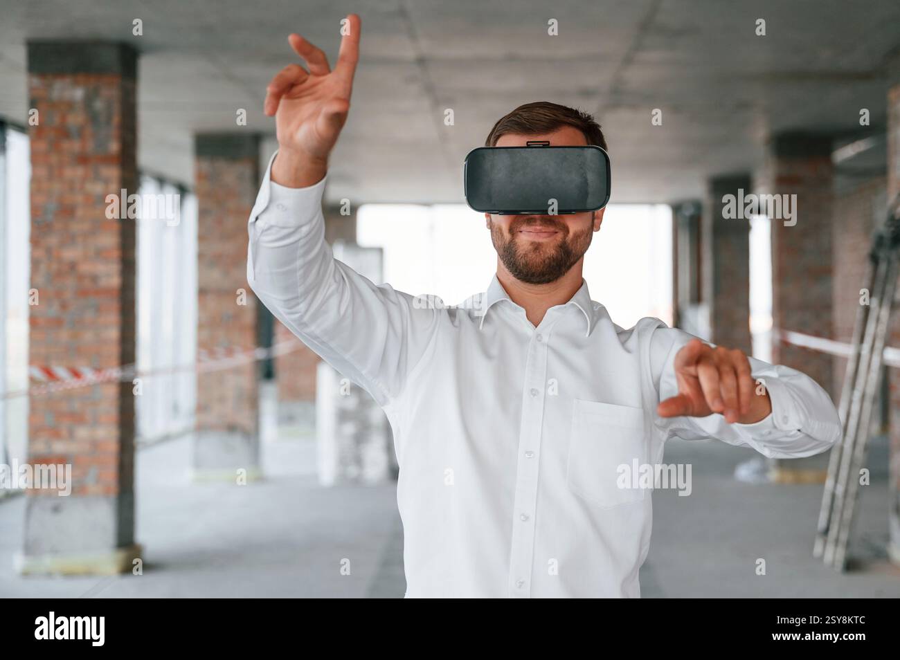 On the construction site. Man in formal clothes is playing VR game in ...